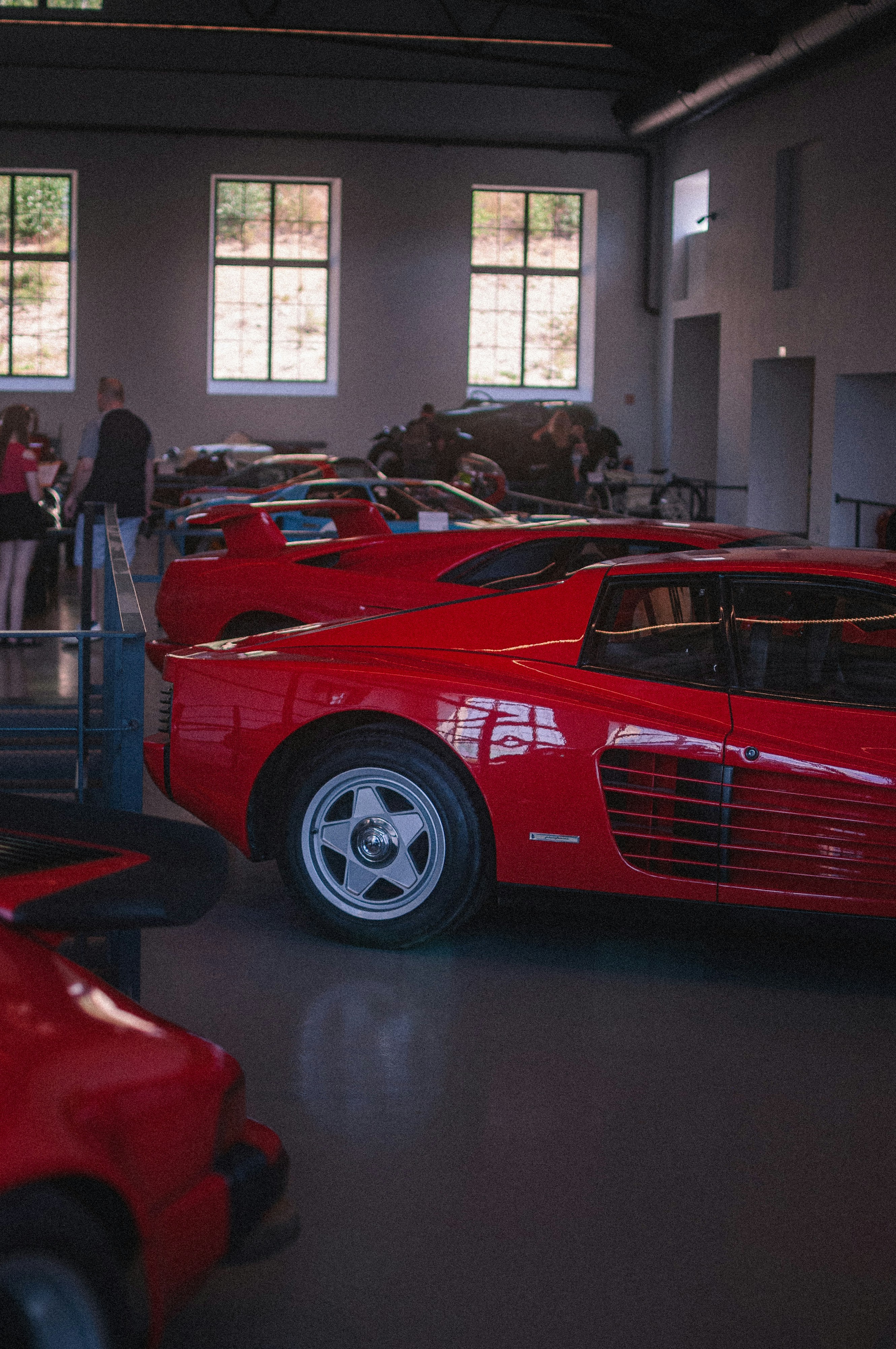 Red sports cars are displayed inside a building.