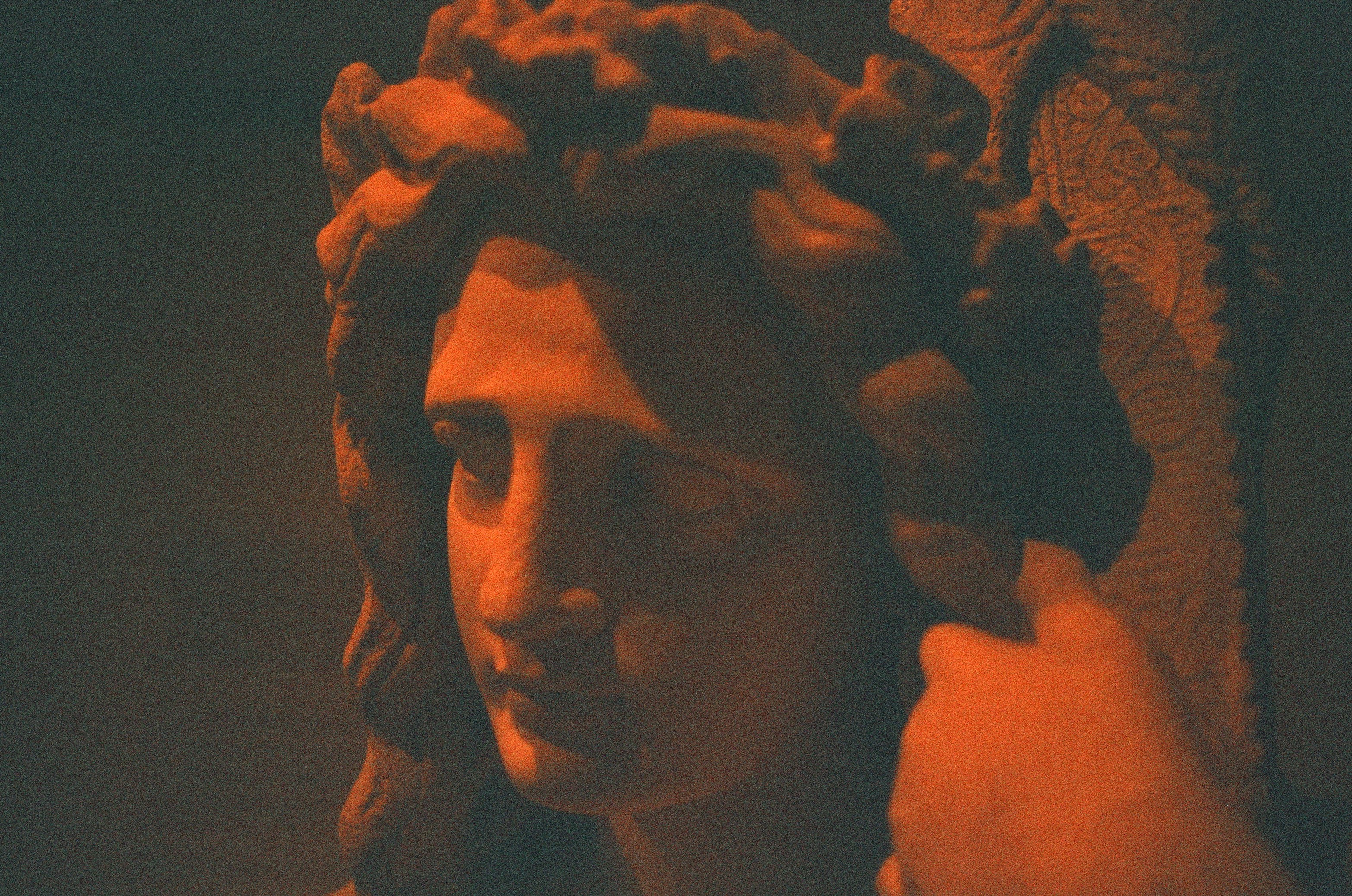 A statue's face glows in an orange hue. photo – Free Portrait Image on ...