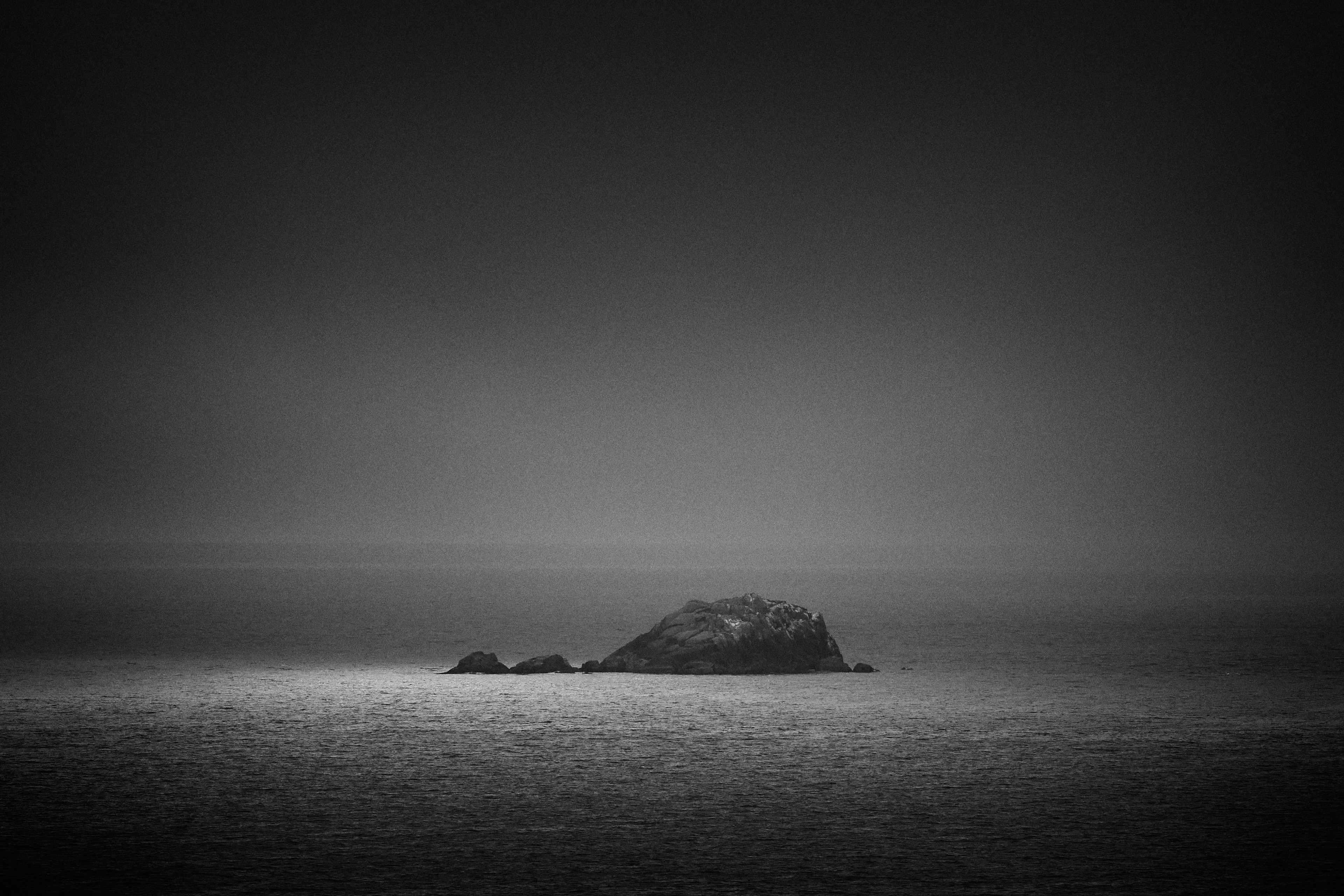 A lonely island sits in a calm ocean.