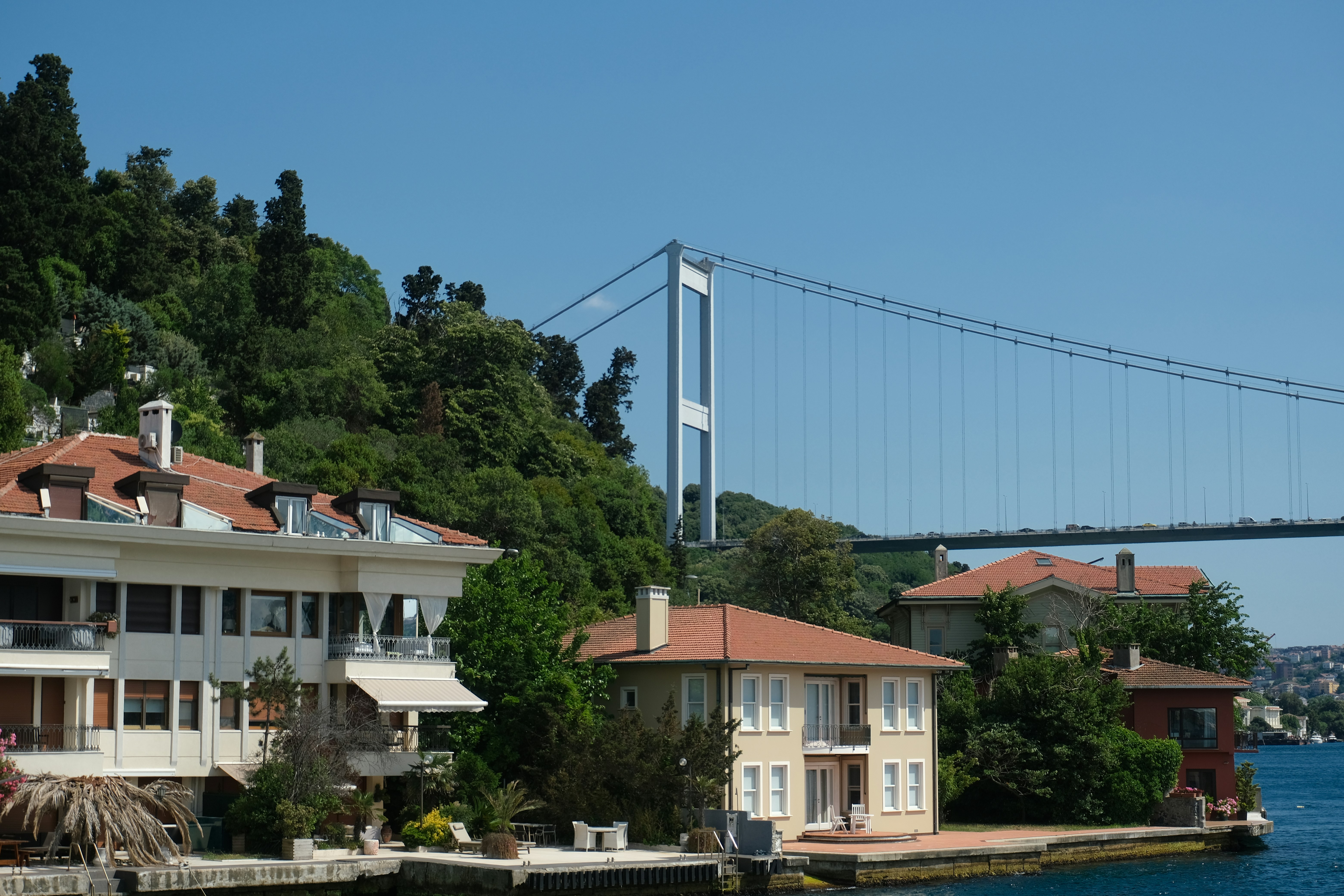 Charming waterfront houses nestled along the coast with a modern bridge spanning above, showcasing a blend of nature and architecture.