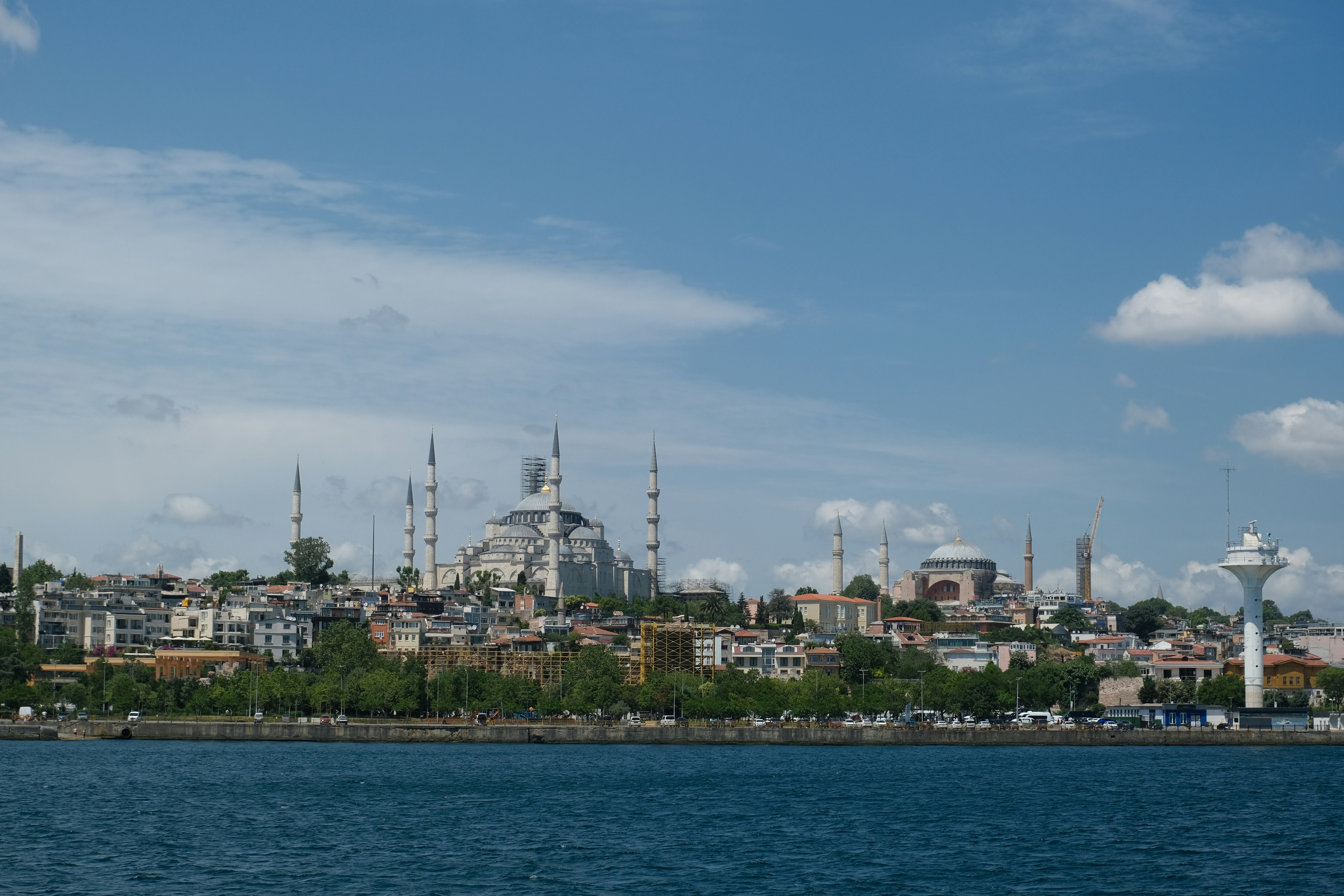 Historic skyline of Istanbul featuring prominent mosques and a water tower, framed by lush greenery along the waterfront.
