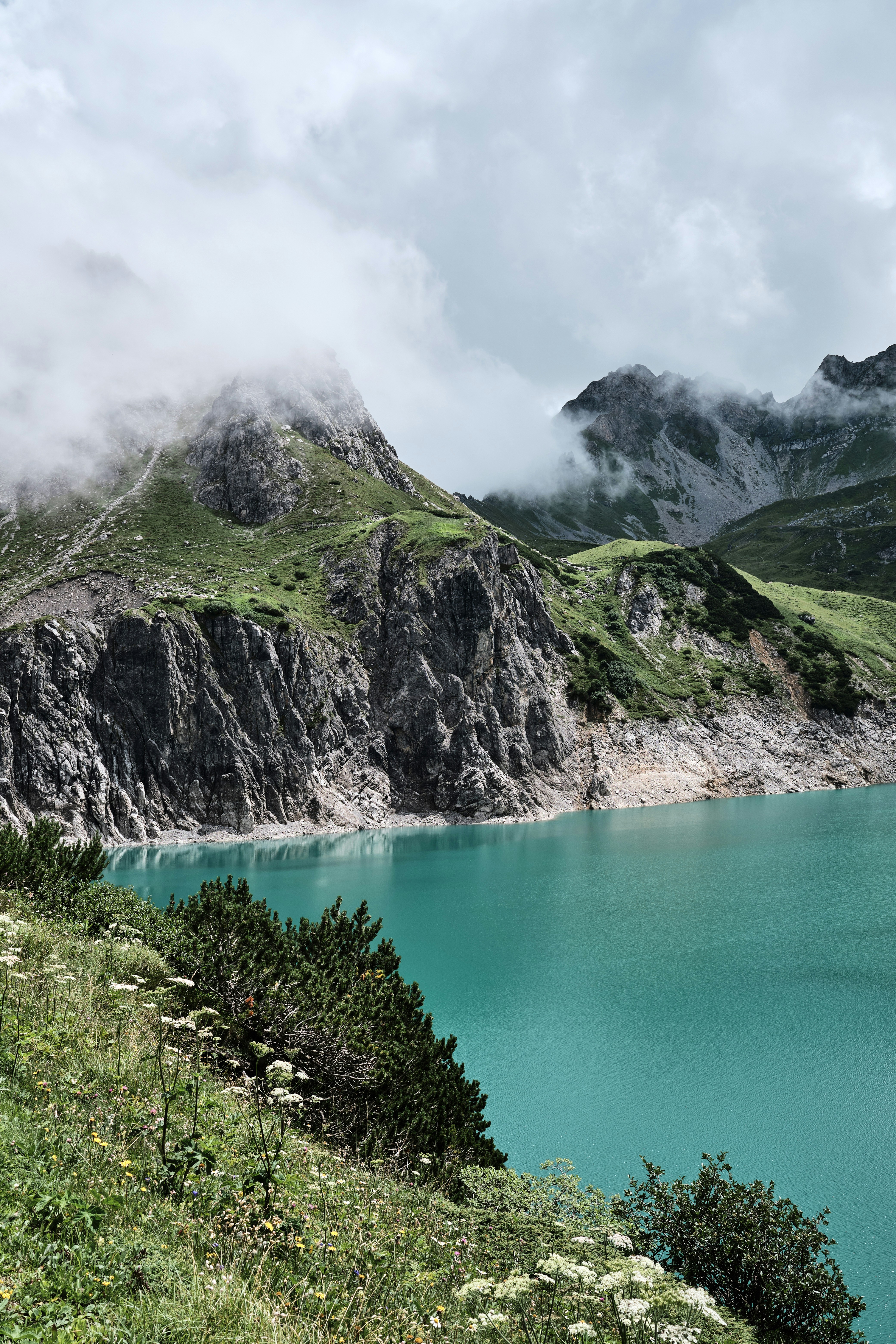 Cloudy mountains overlook a vibrant turquoise lake.