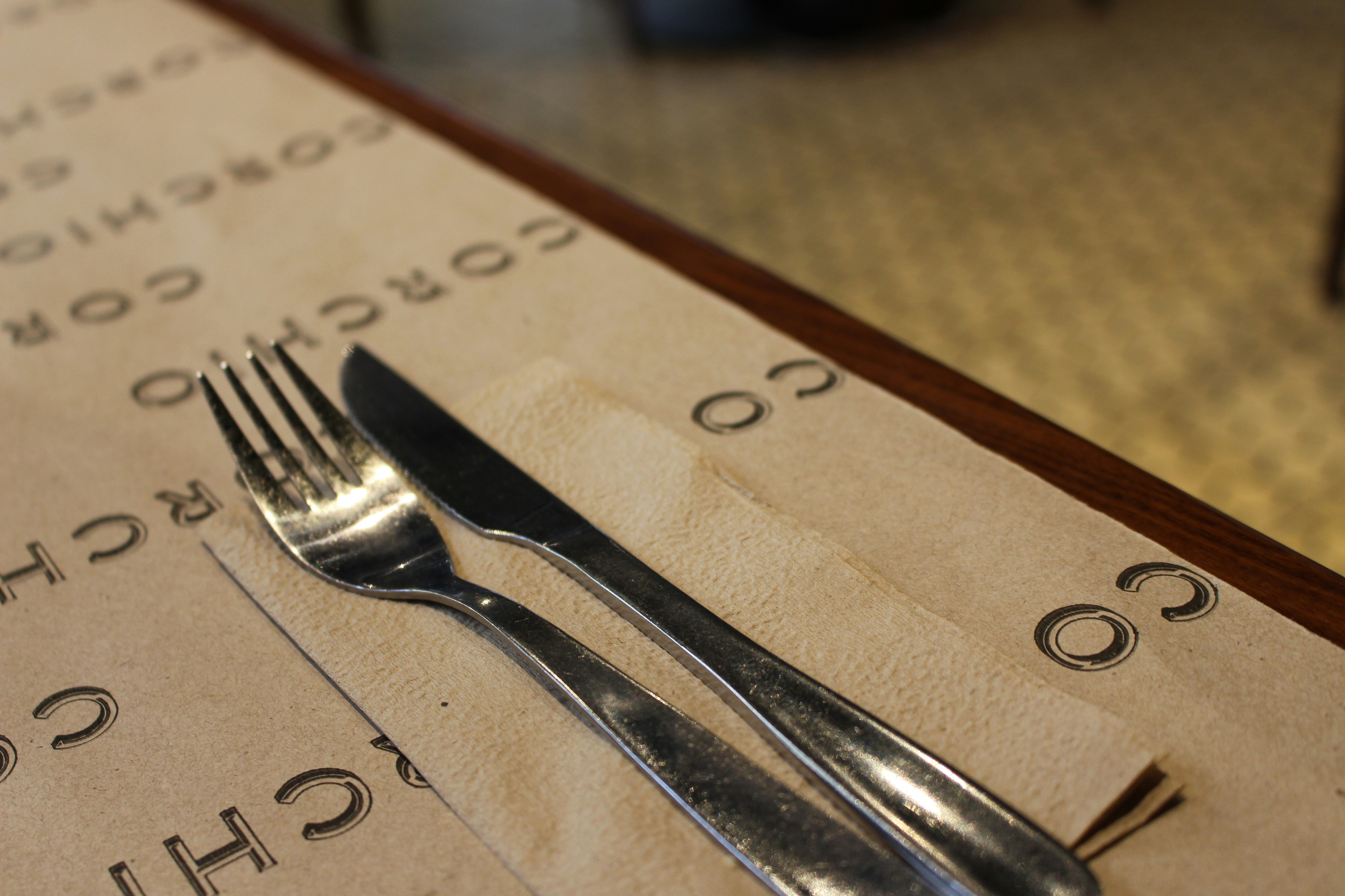 Set of cutlery, a fork and a knife | A fork and knife rest on a table.