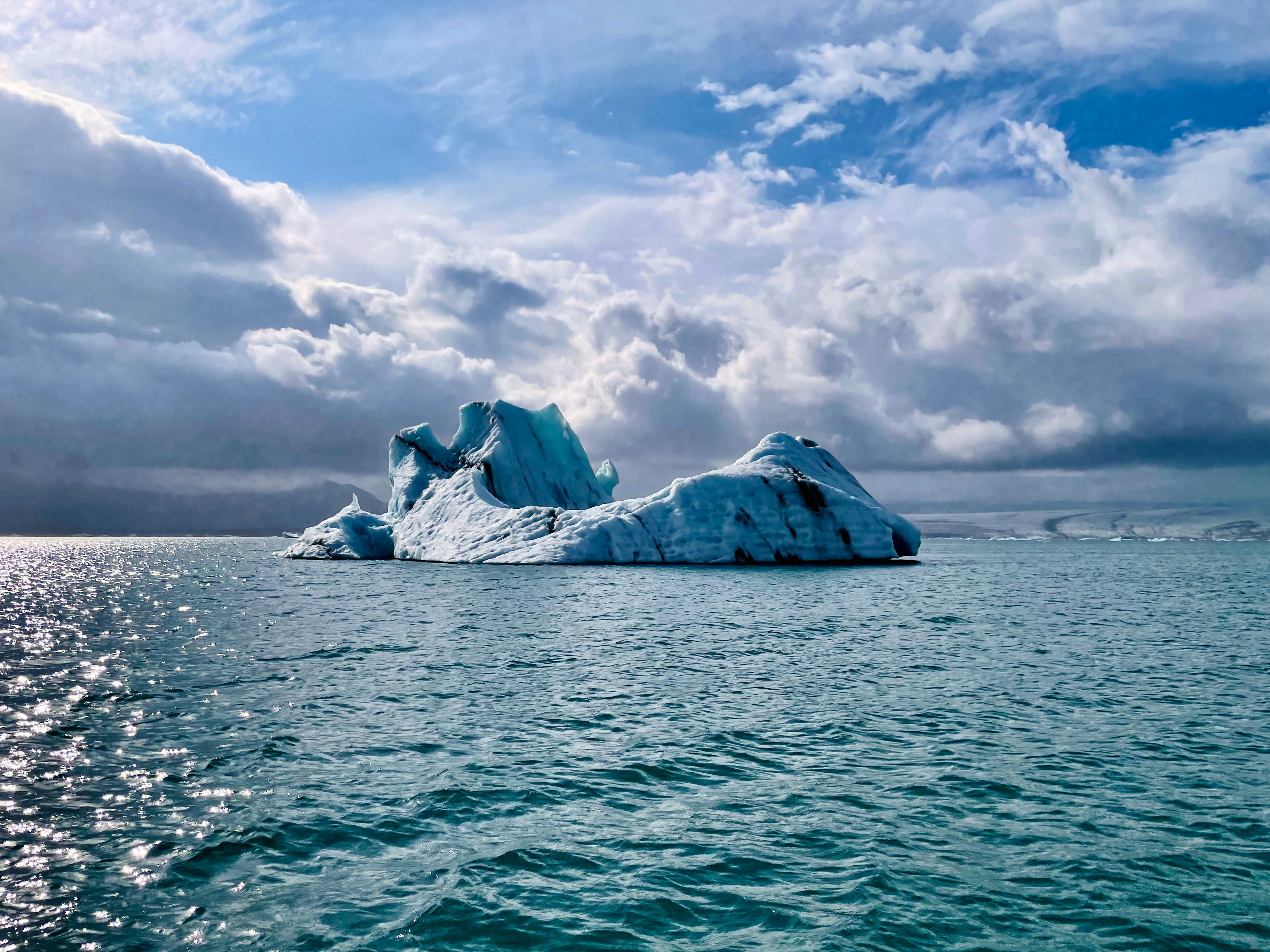 Tip of an iceberg in the lagoon of Jokulsarlon, Hofn, Iceland. | An iceberg floats serenely on the calm ocean.
