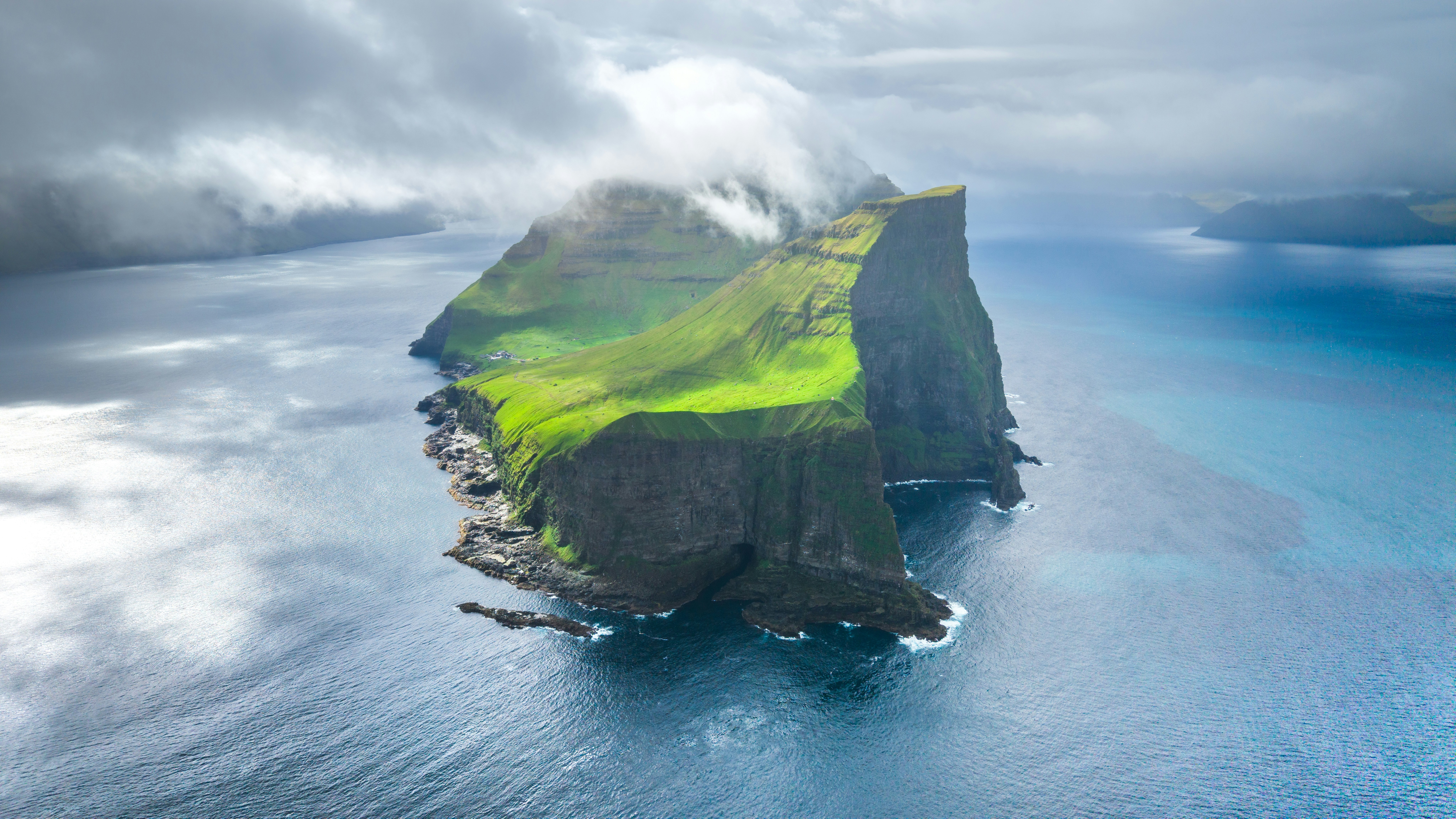 Green island rises from the ocean with dramatic cliffs.