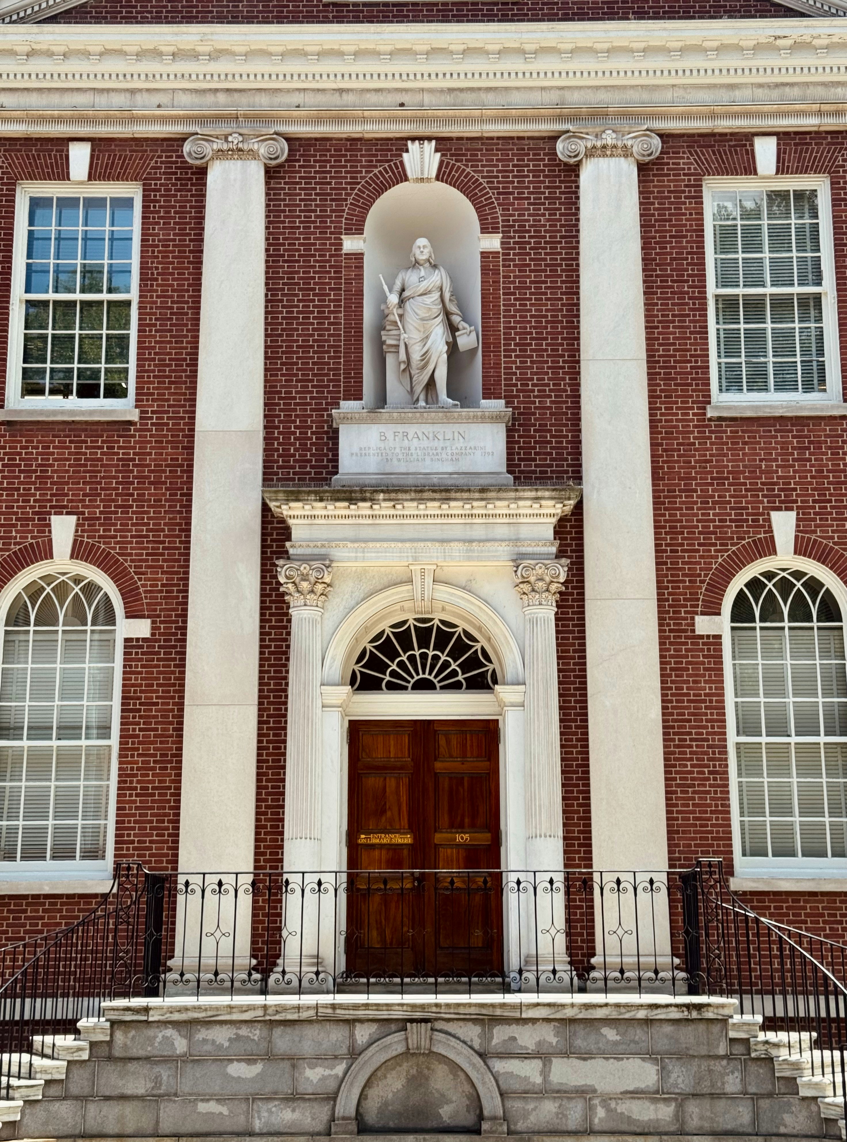 A brick building with columns and a statue.