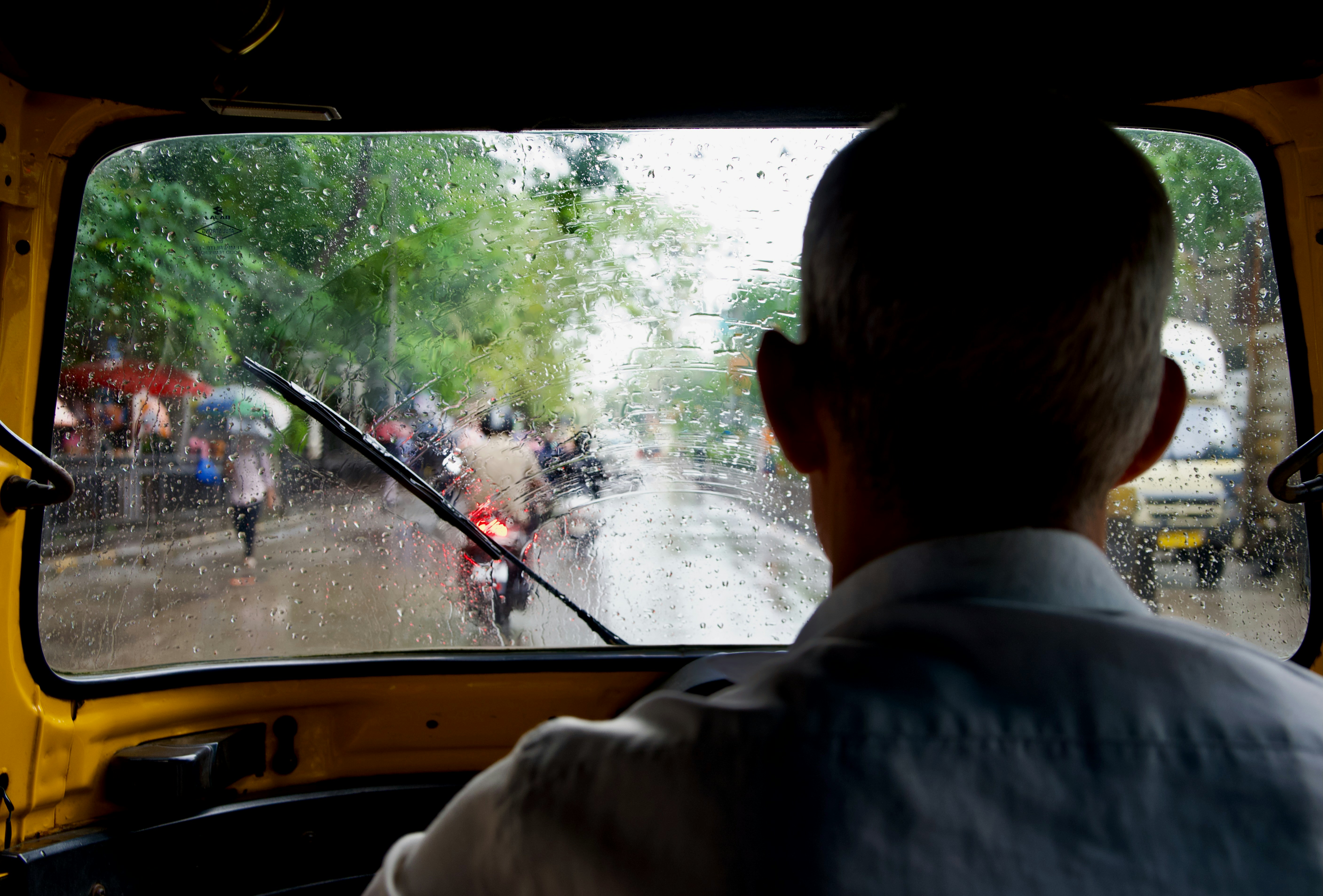 Backseat Rain: A Yellow Taxi Window Framed by a Busy Monsoon Street