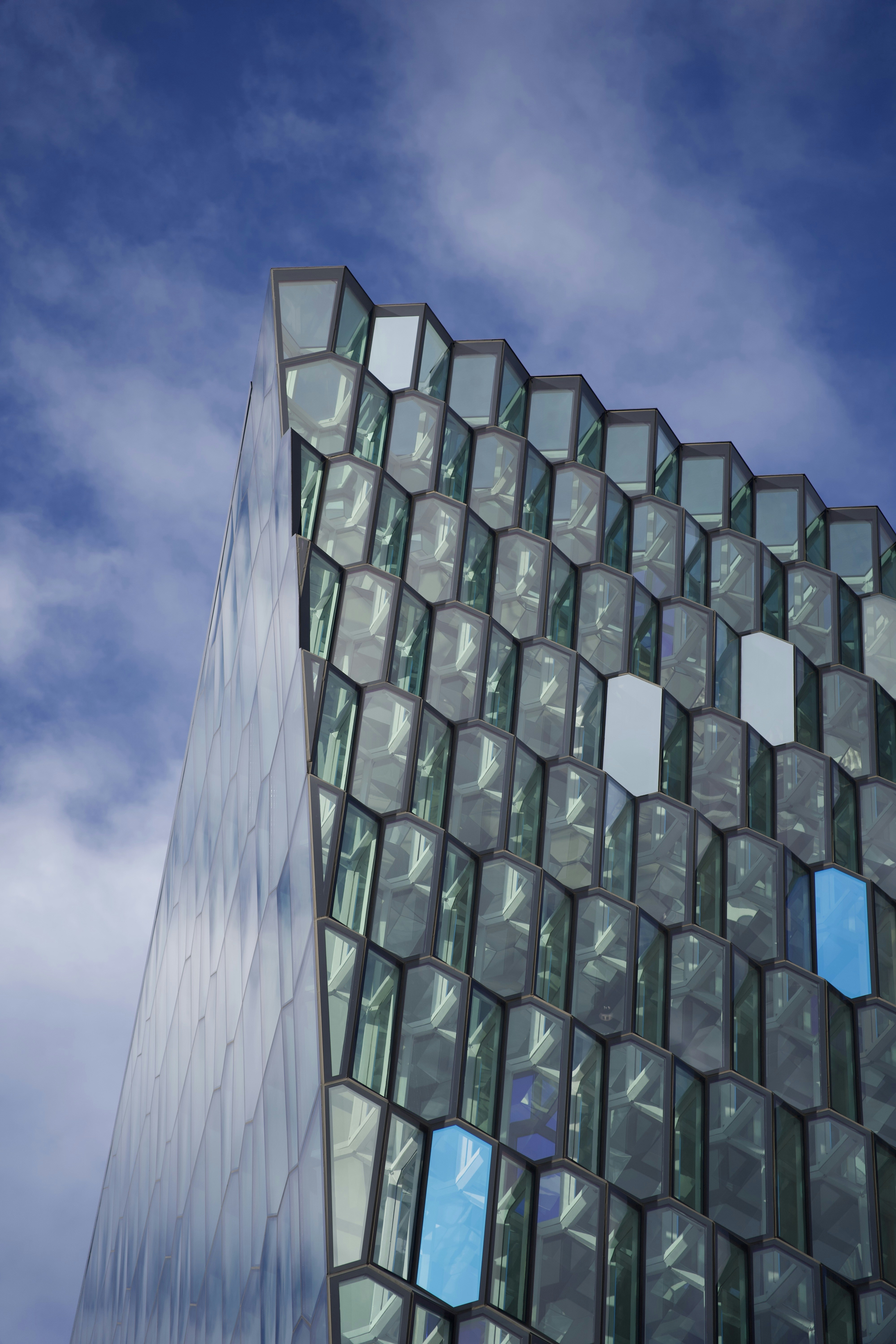 View of the Icelandic Harpa Concert Hall in Reykjavik. | A modern building features hexagonal glass windows.