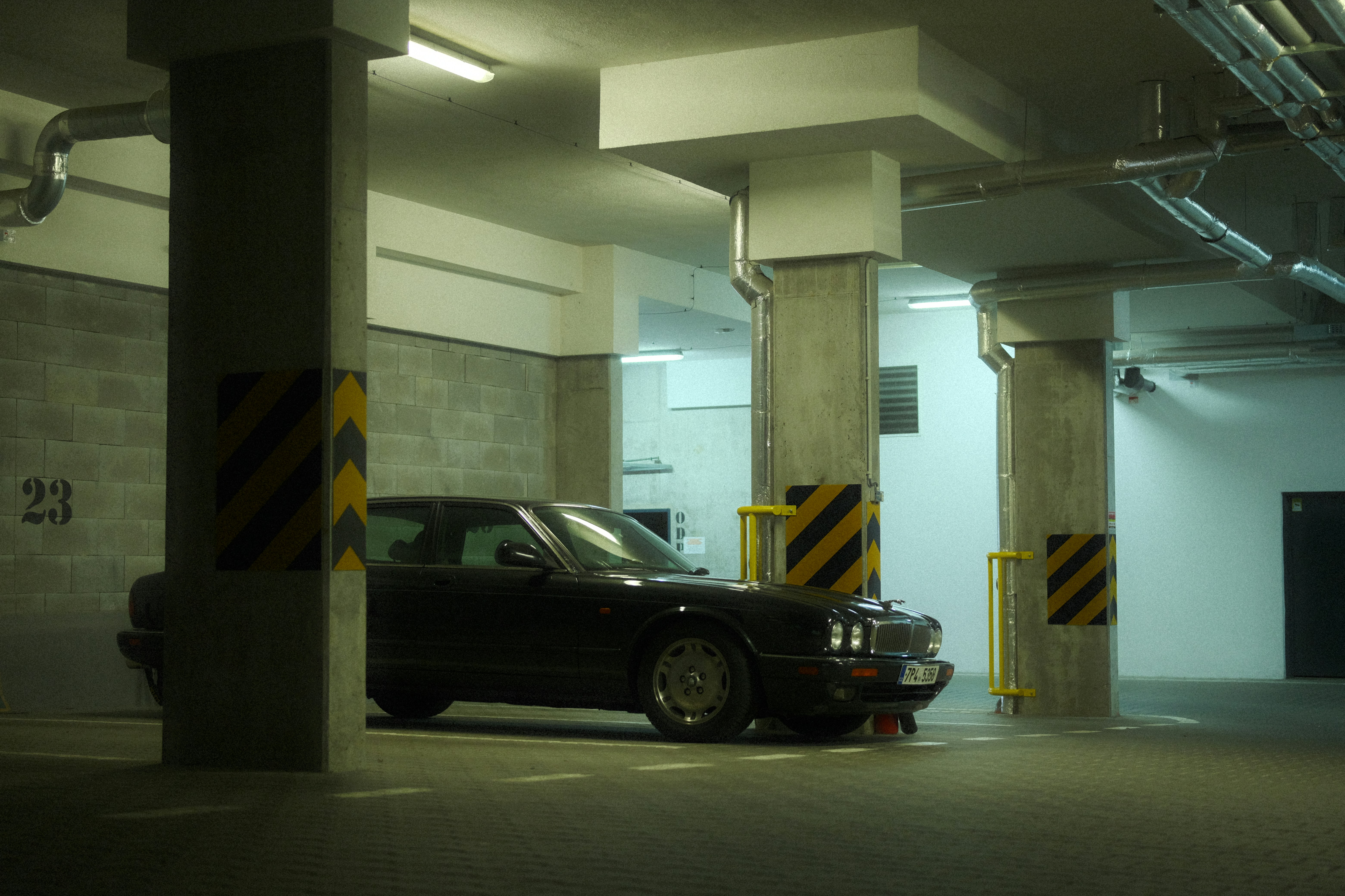 Jaguar XJ8. Classic black sedan parked in underground garage. | A dark car parked inside a parking garage.