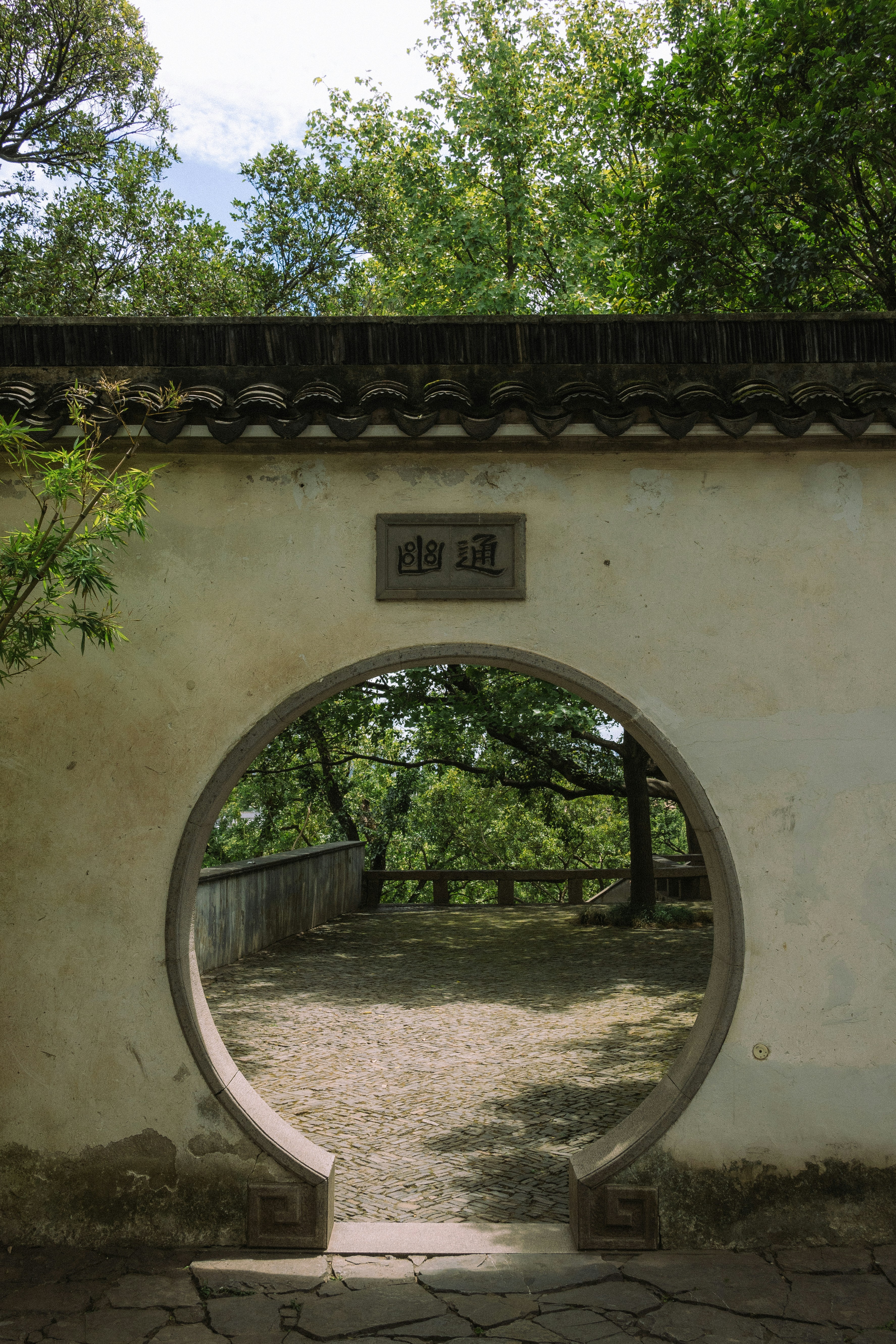 A round archway frames a lush, green landscape.
