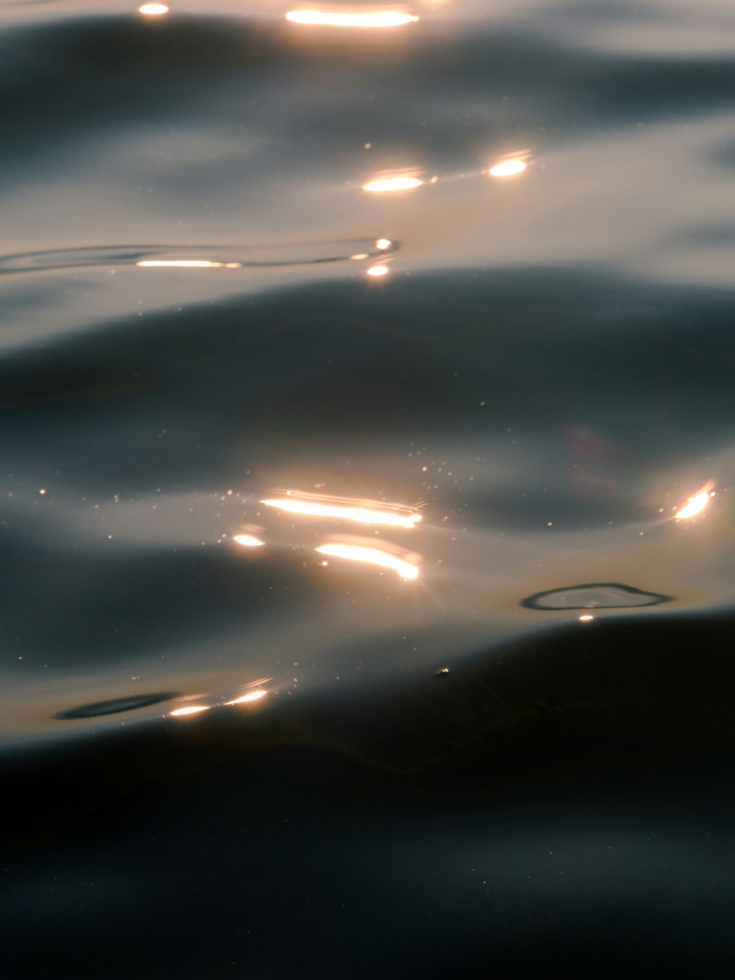 close up of small waves at golden hour | Sunlight glistens on gentle water waves.