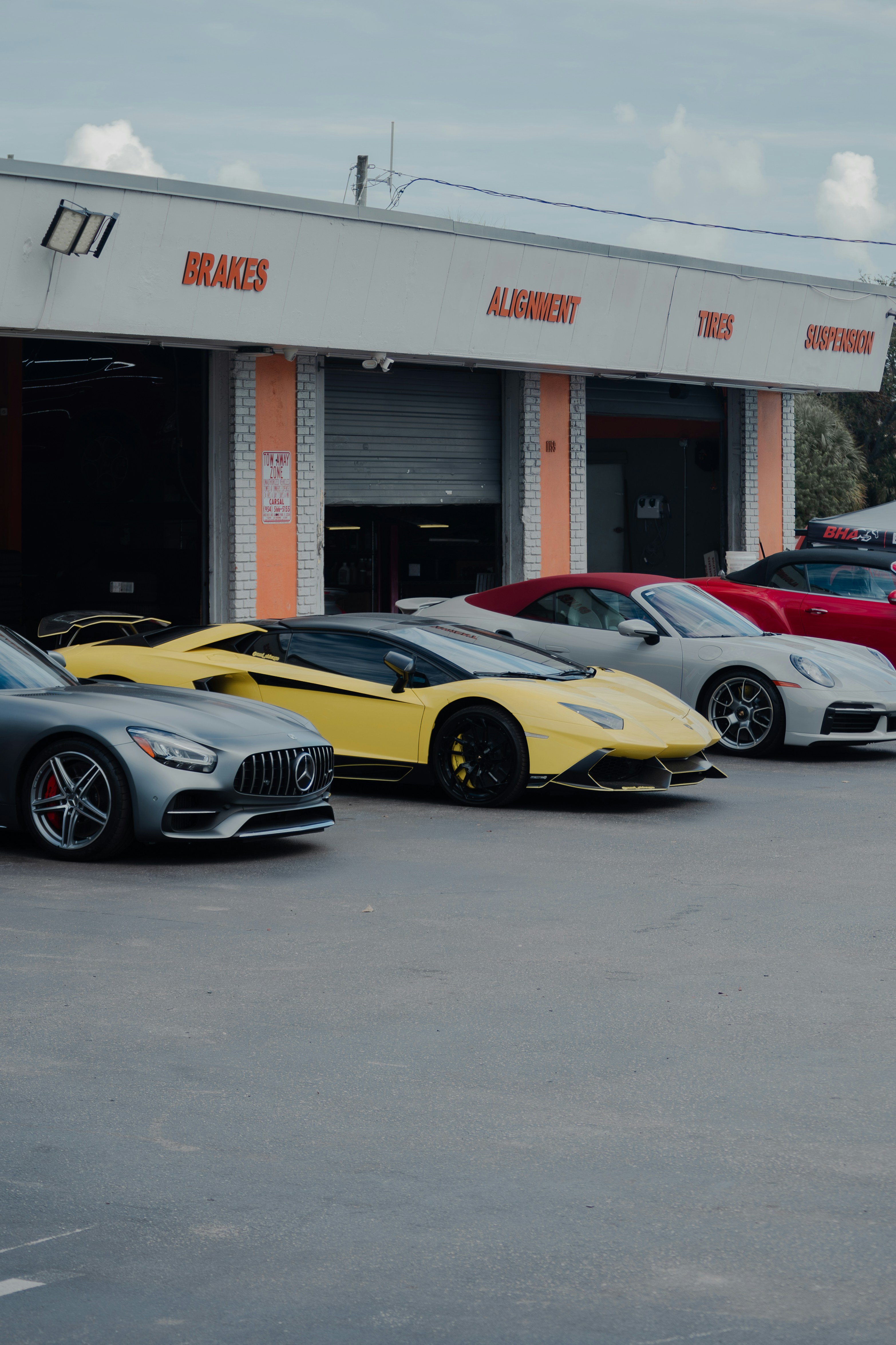 Luxury cars are parked outside a shop.