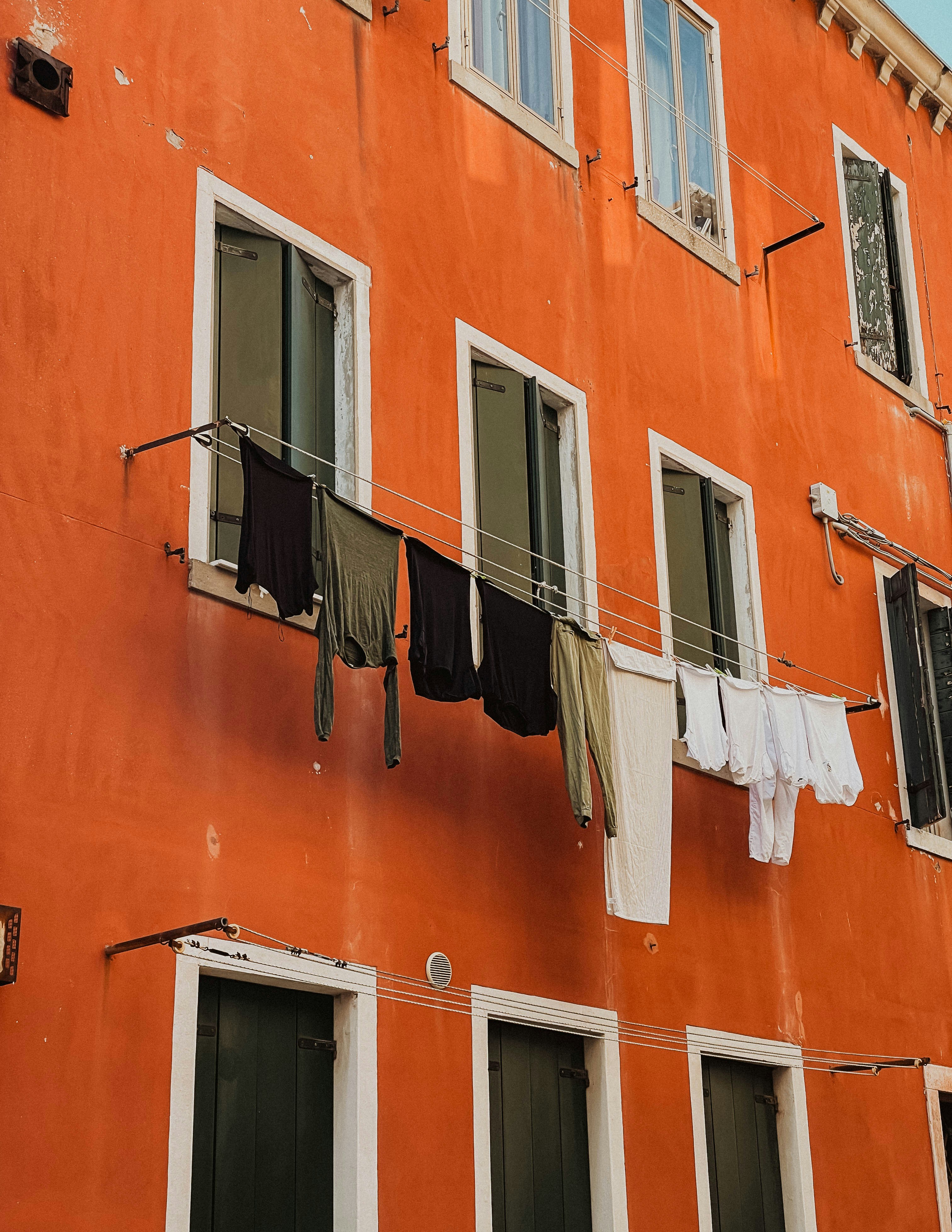 Laundry hangs outside an orange building's windows.