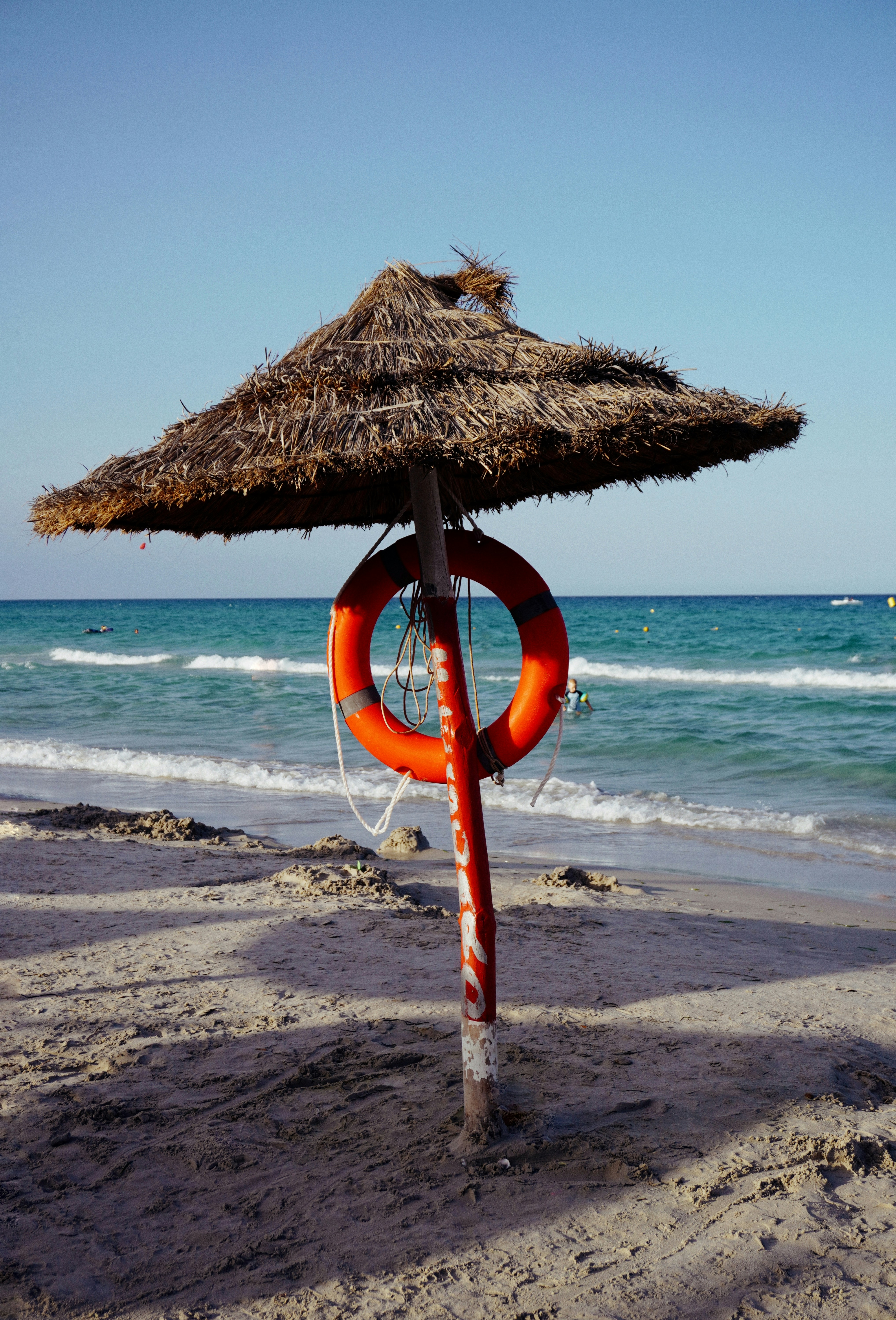 The Orange Sentinel Beneath a Straw Beach Umbrella