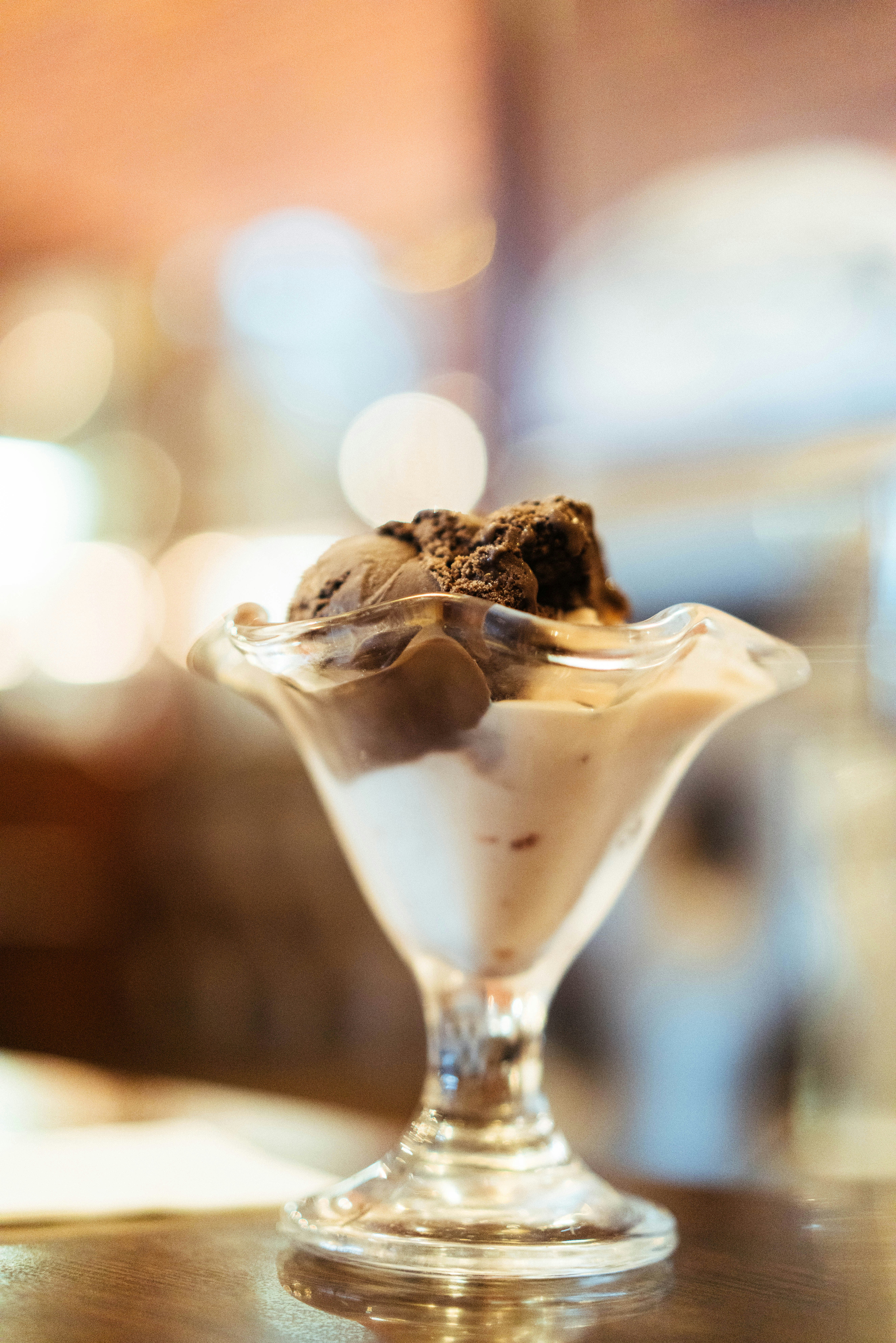 Delicious ice cream topped with chocolate crumbs in a clear glass sundae dish. The soft focus background enhances the dessert's allure.