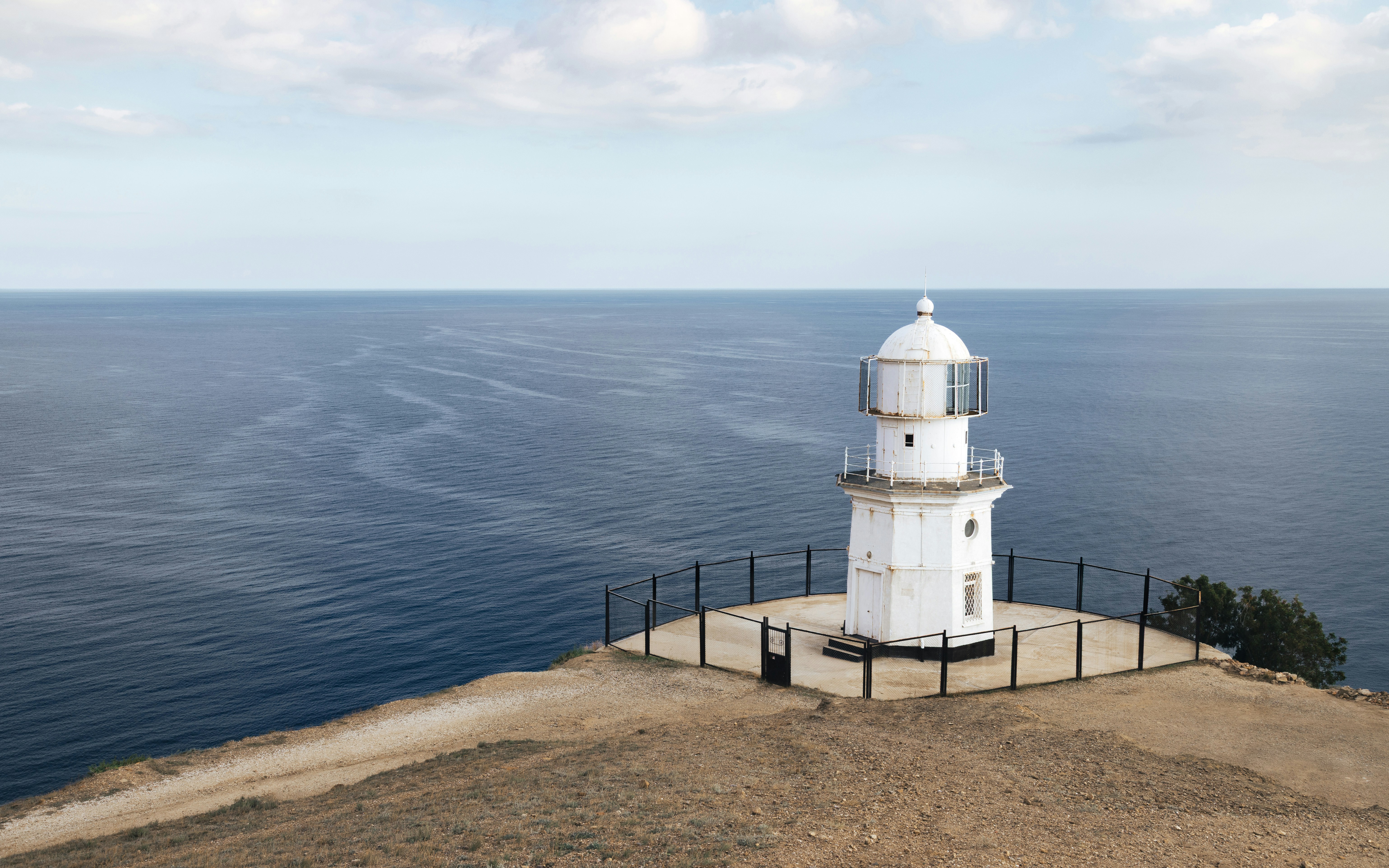 A white lighthouse stands guard over the ocean. photo – Free Wallpaper ...