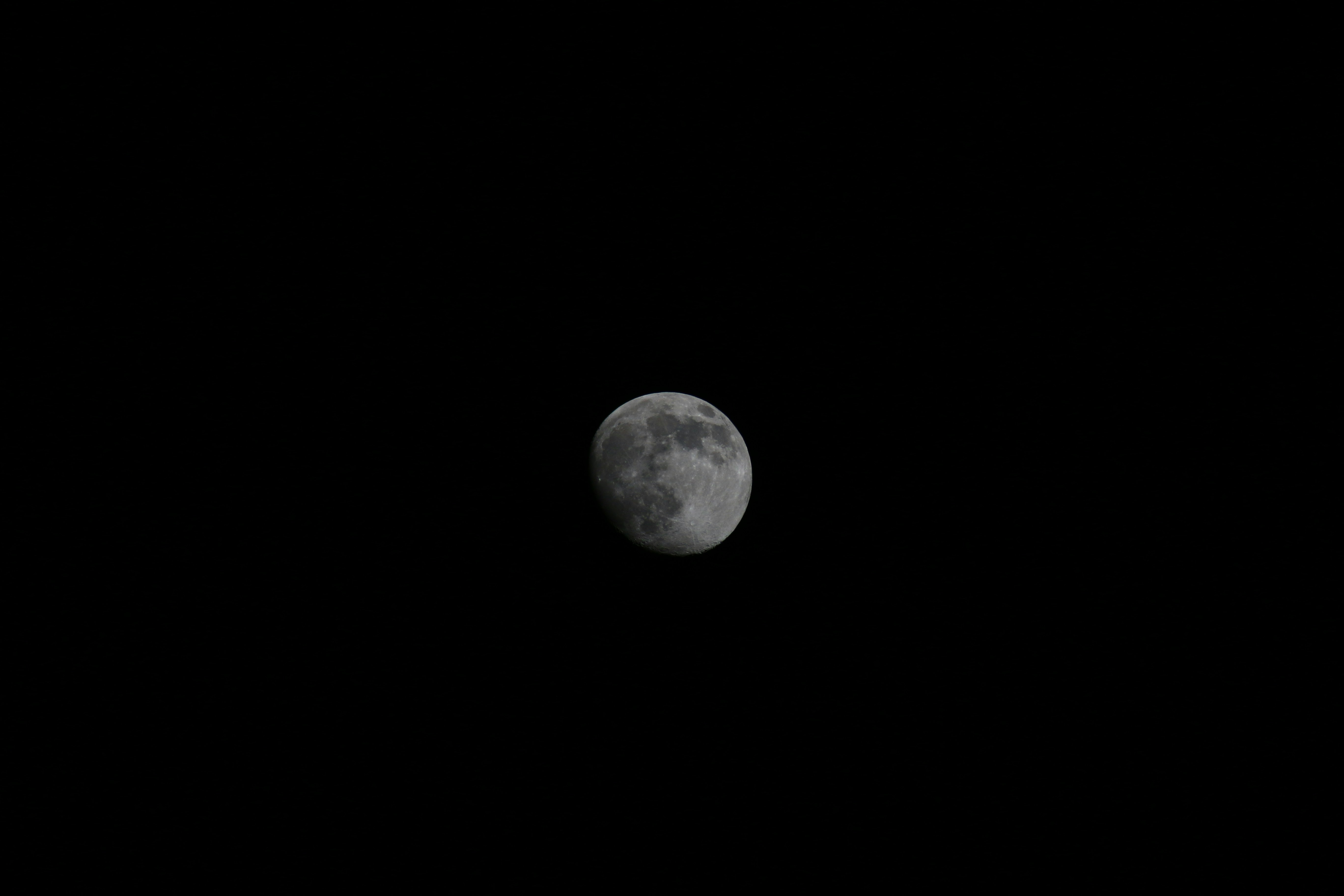 The moon in a waning phase, elegantly set against a deep black sky, showcasing its craters and textures.
