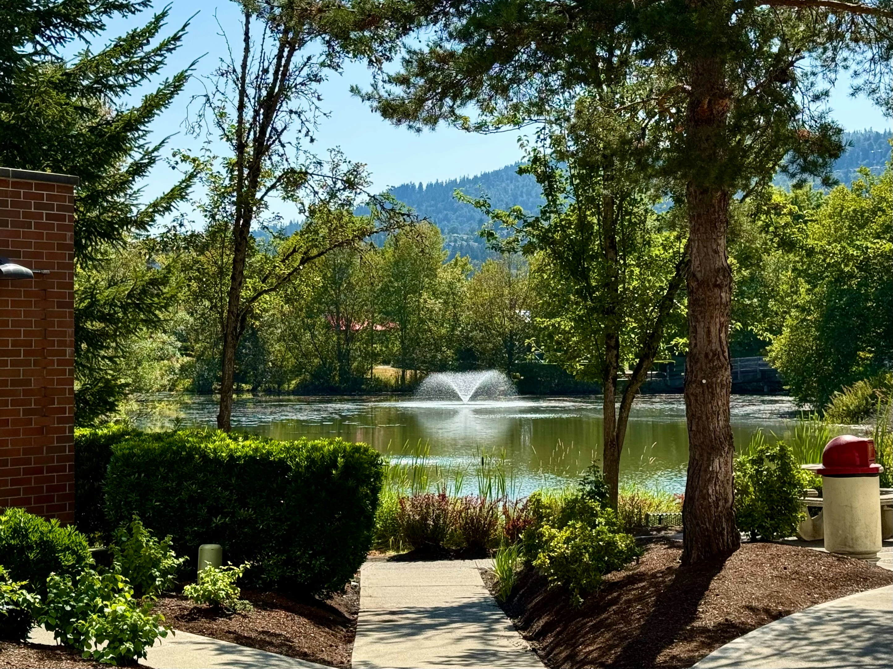 Midday Serenity: Fountain, Trees, and Lake at the Riverside Campus
