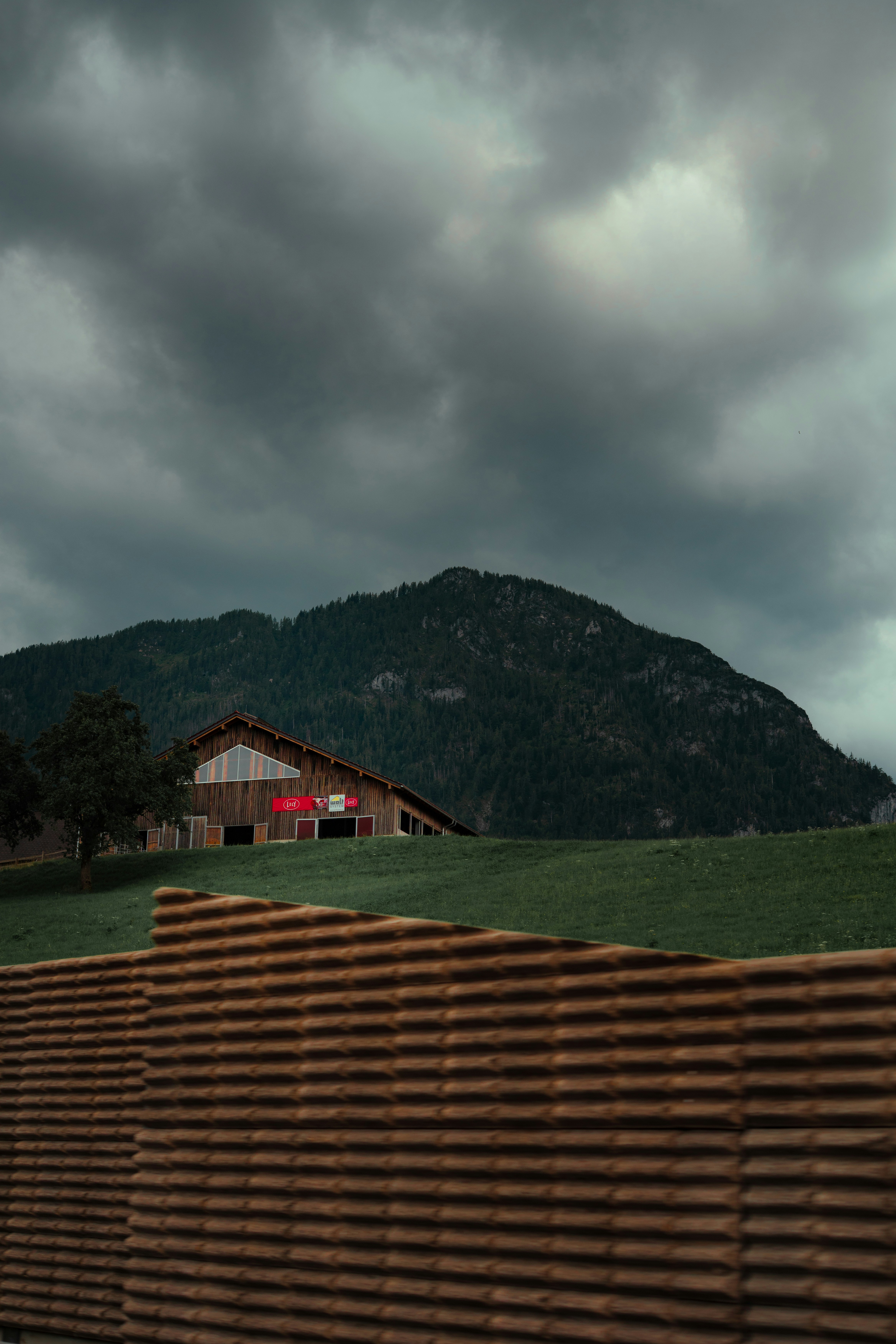 Red Sign on a Hillside Barn Beneath a Tempestuous Sky