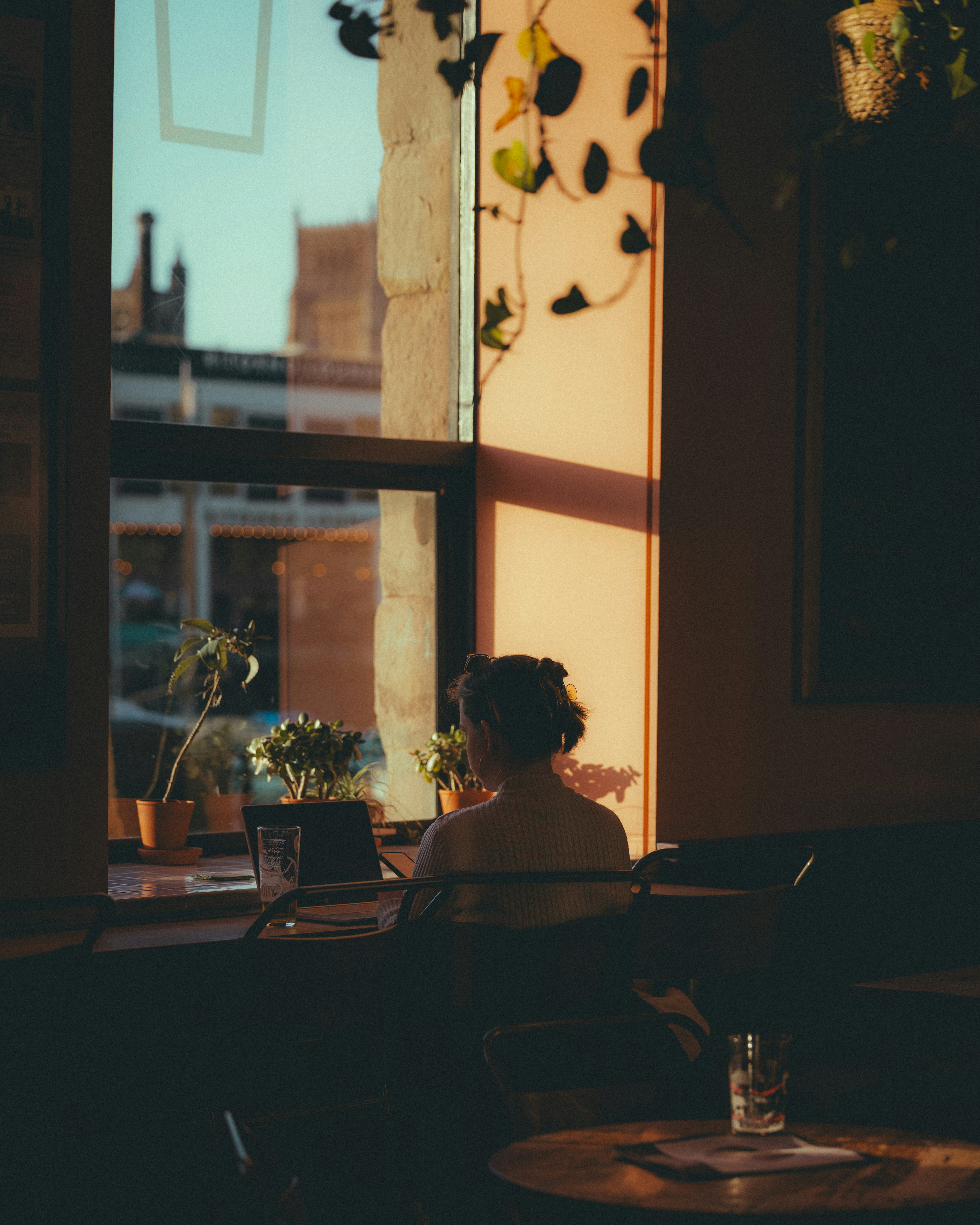 A woman works by a sunny window.