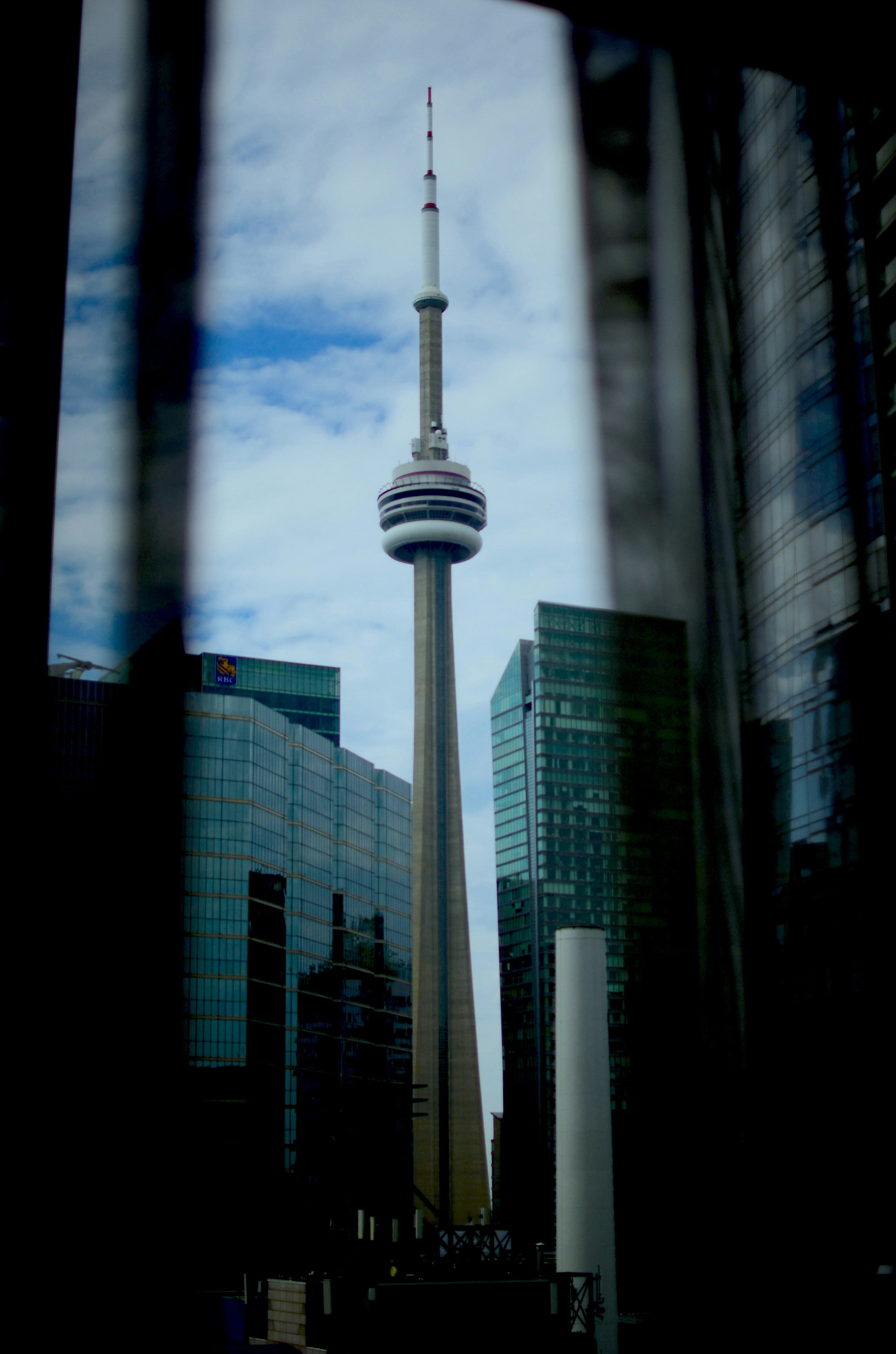 CN Tower in Downtown Toronto as seen through curtains of a hotel | The cn tower framed between city buildings.