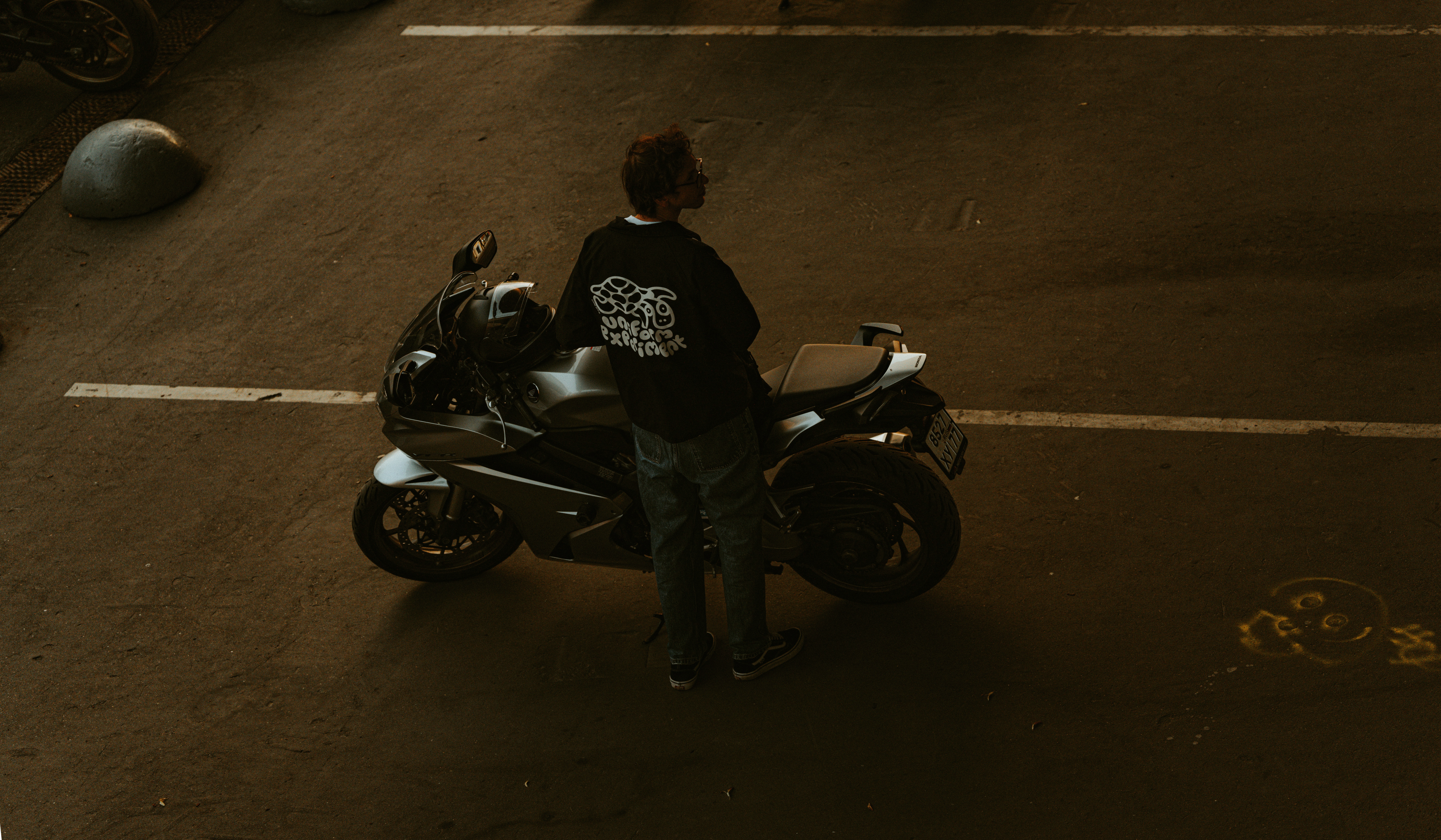 A person stands beside a motorcycle.