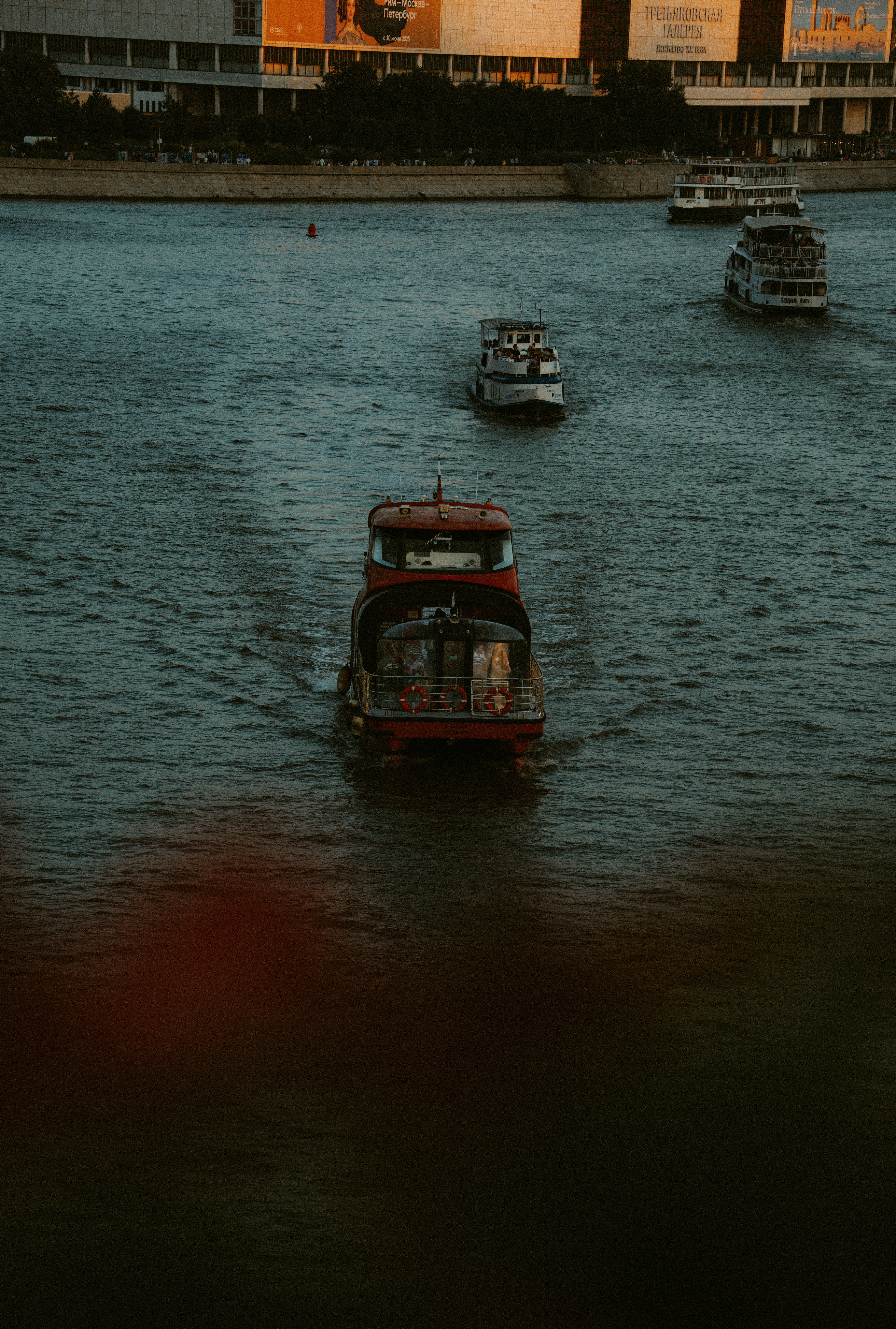 Boats sail on the water near a city.