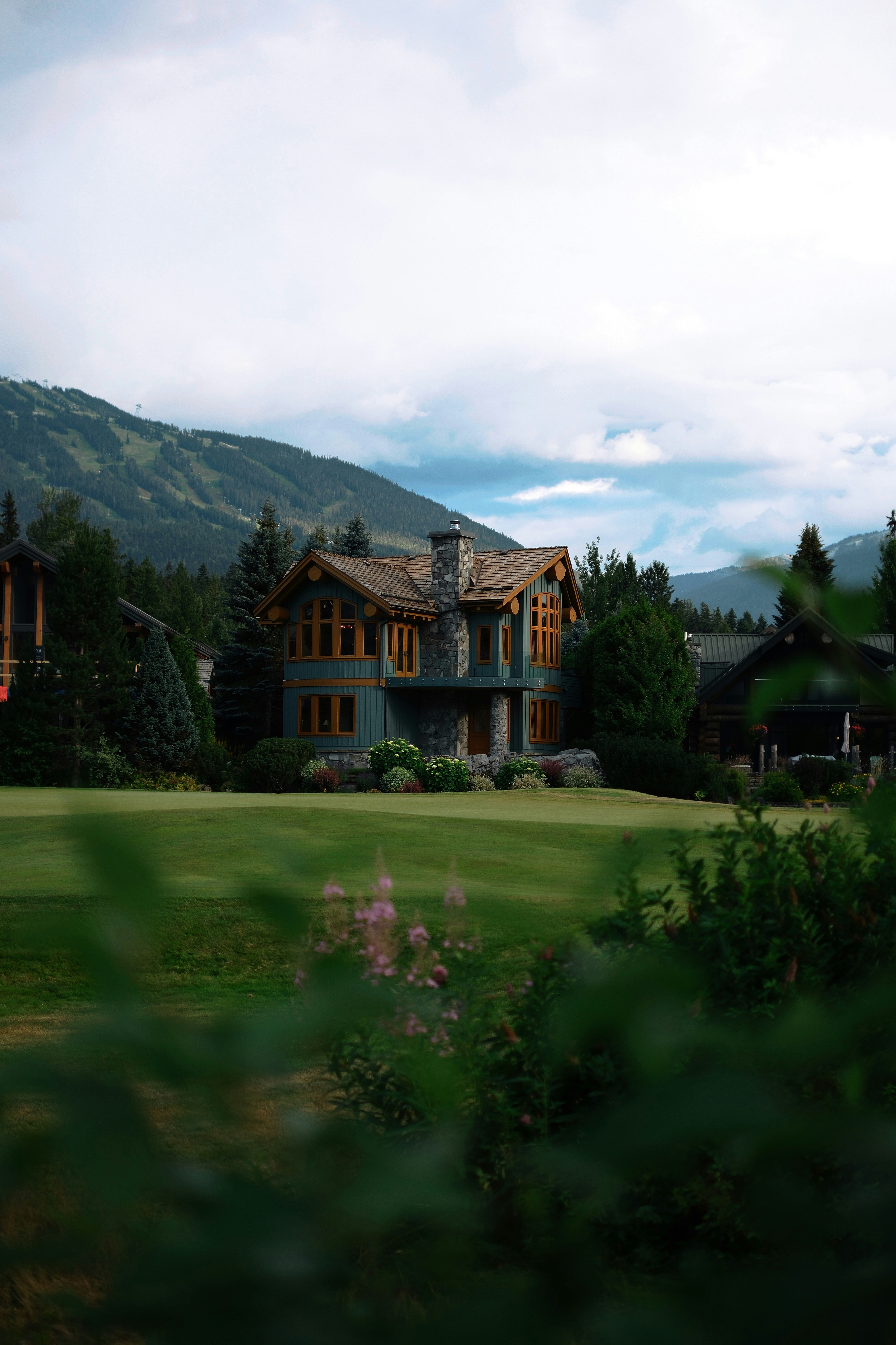 Charming mountain house nestled among lush greenery and rolling hills, showcasing a blend of rustic and modern design elements.