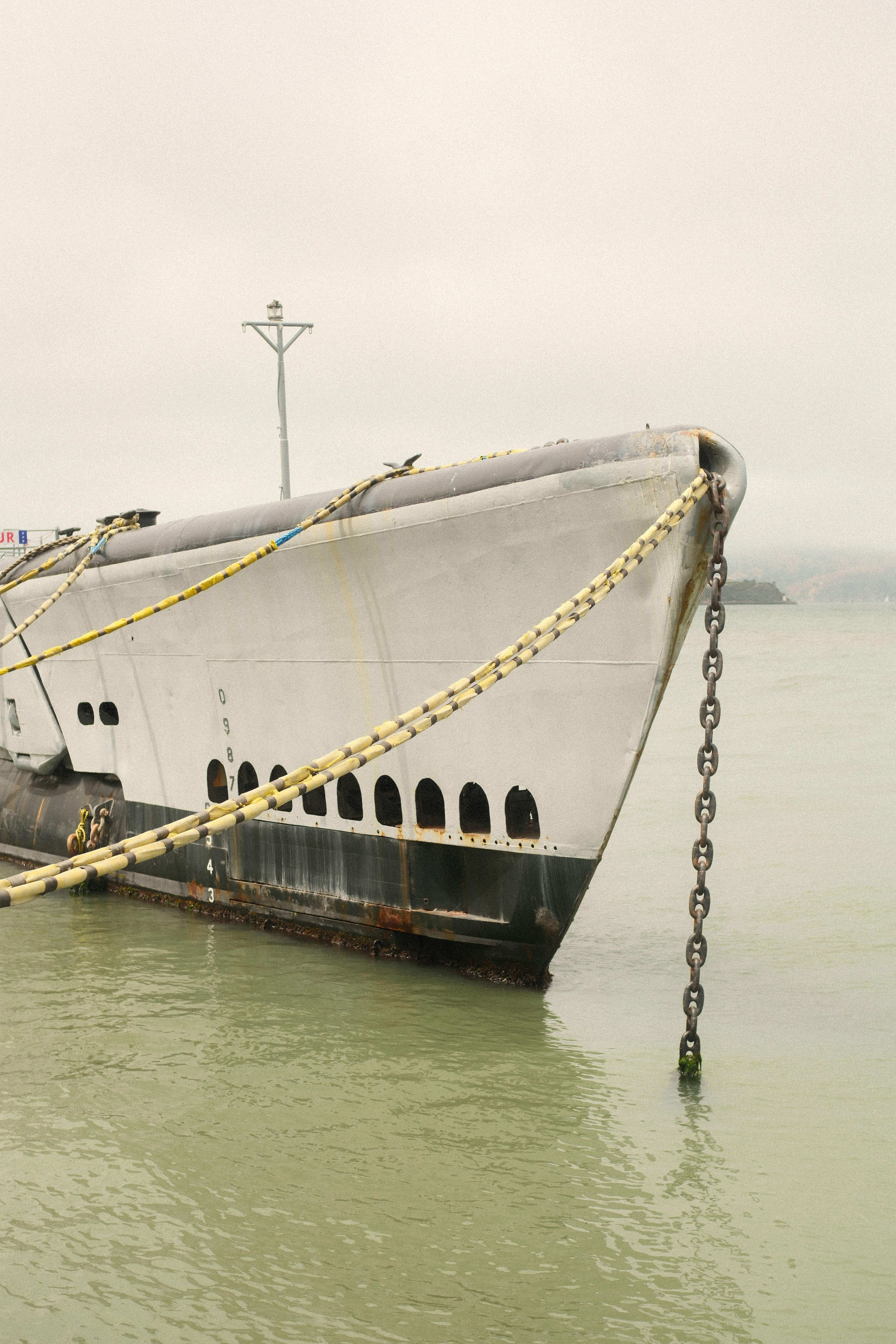 An old submarine is moored at a pier.