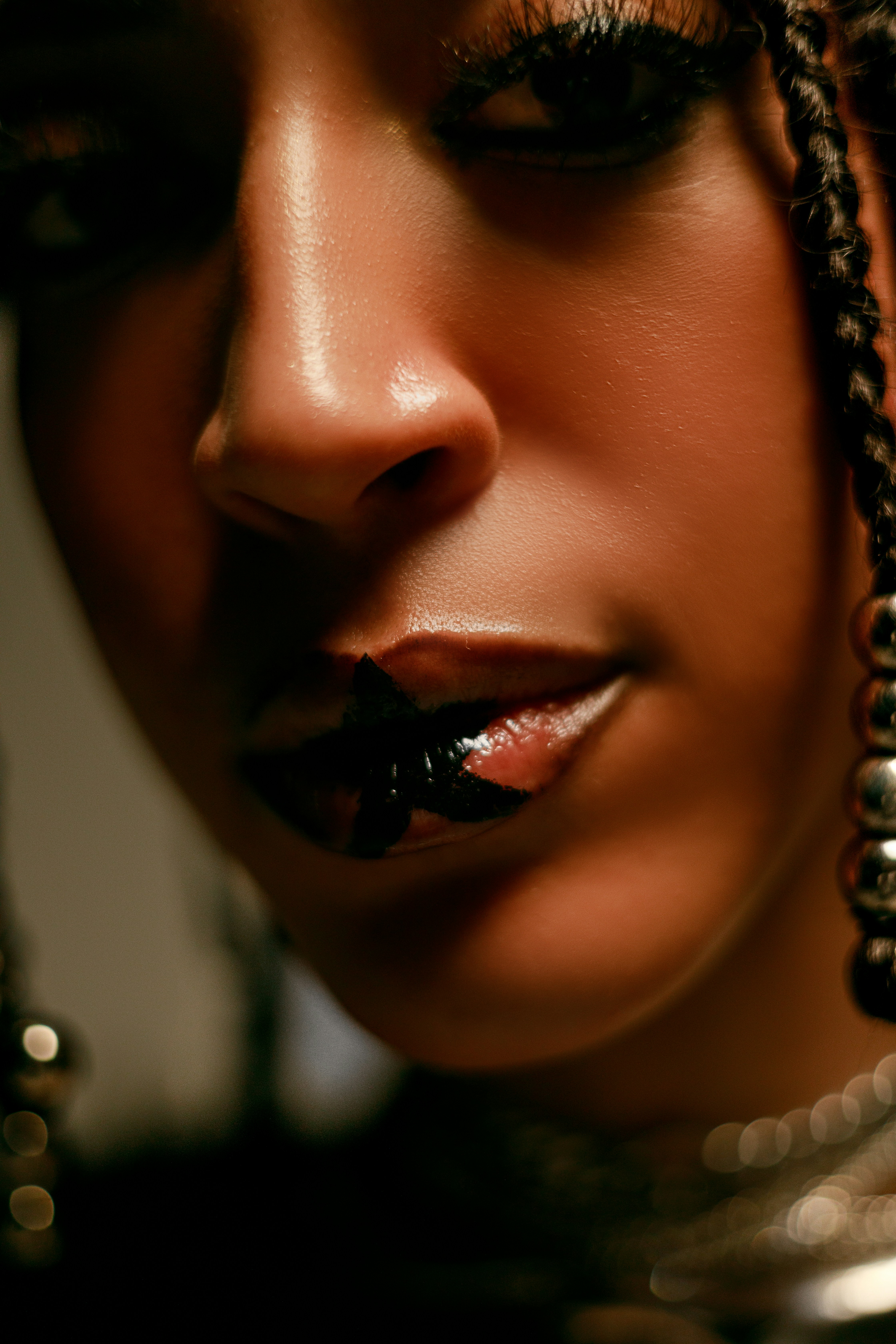 Close-up portrait of a person with intricate braids and a striking black butterfly design on their lips, highlighting a fusion of beauty and artistry.