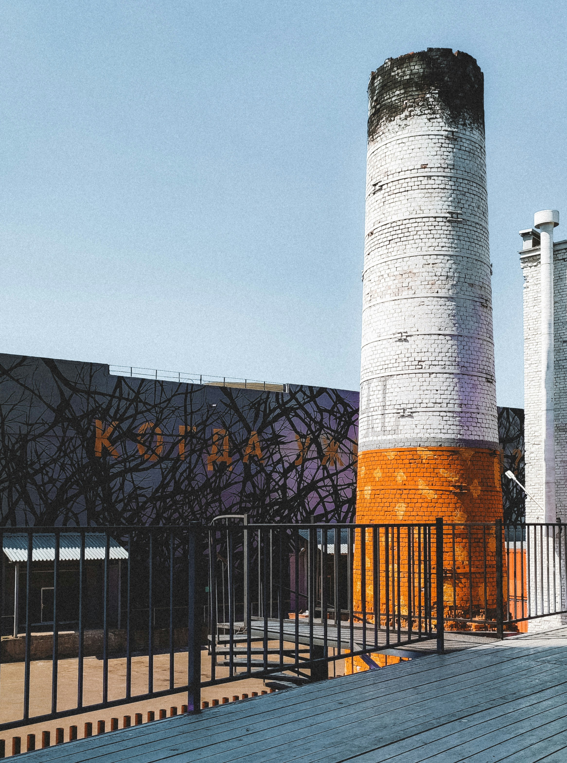 Industrial Chimney and Art Space | A tall chimney stands beside a modern building.