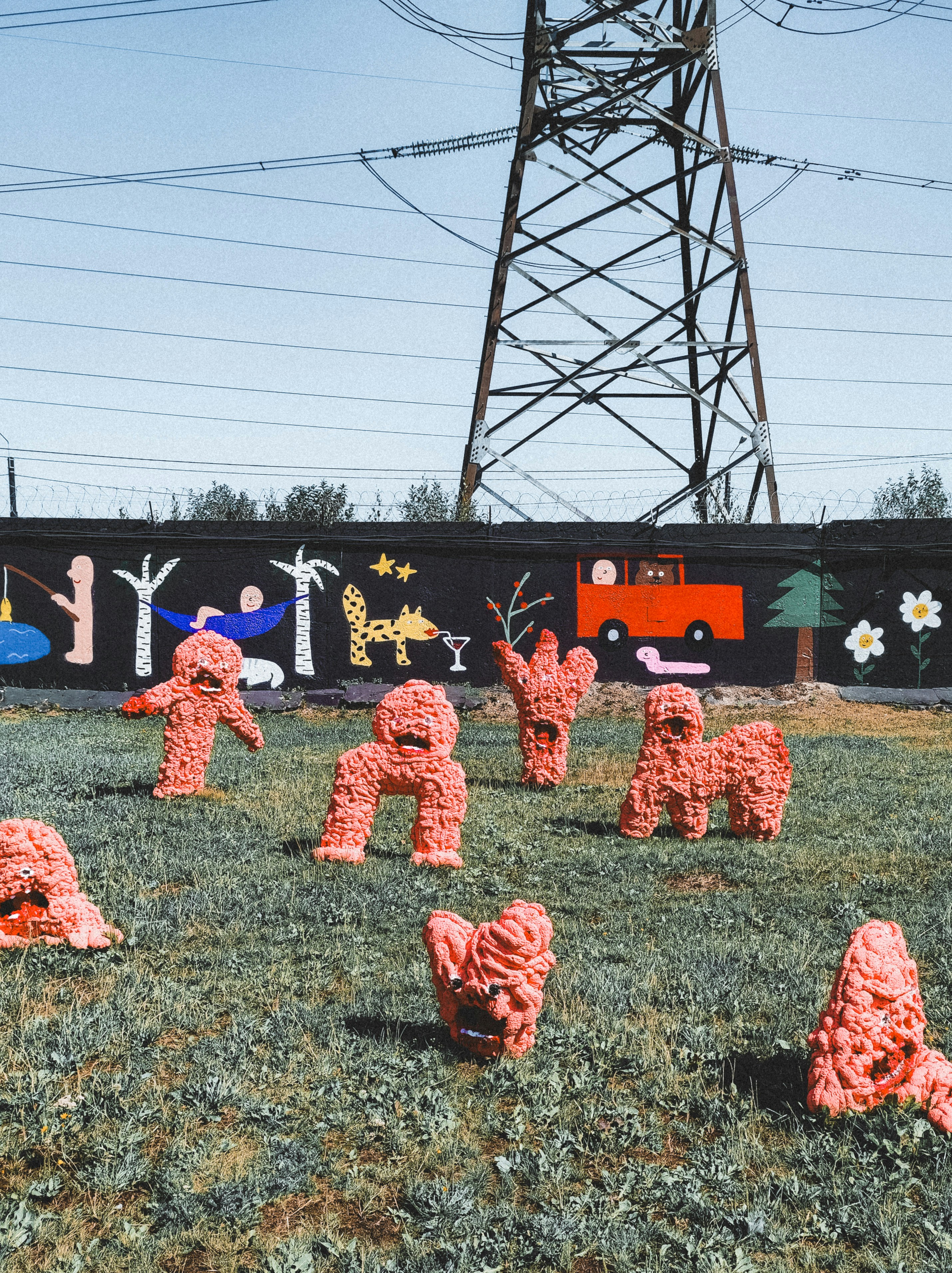 Outdoor Art Installation and Mural | Whimsical sculptures stand before a colorful mural.