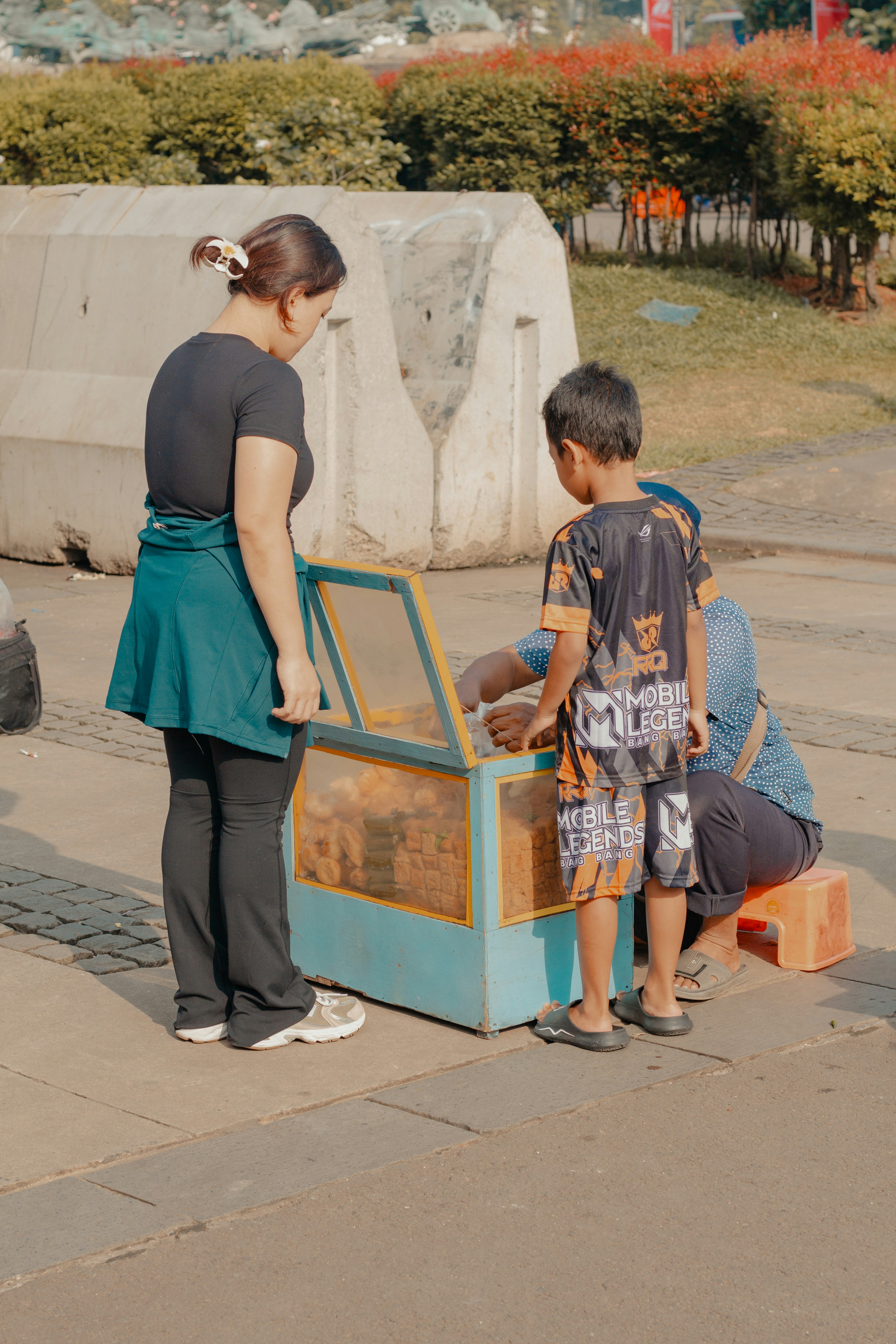 A woman and boy look at a street vendor's cart.