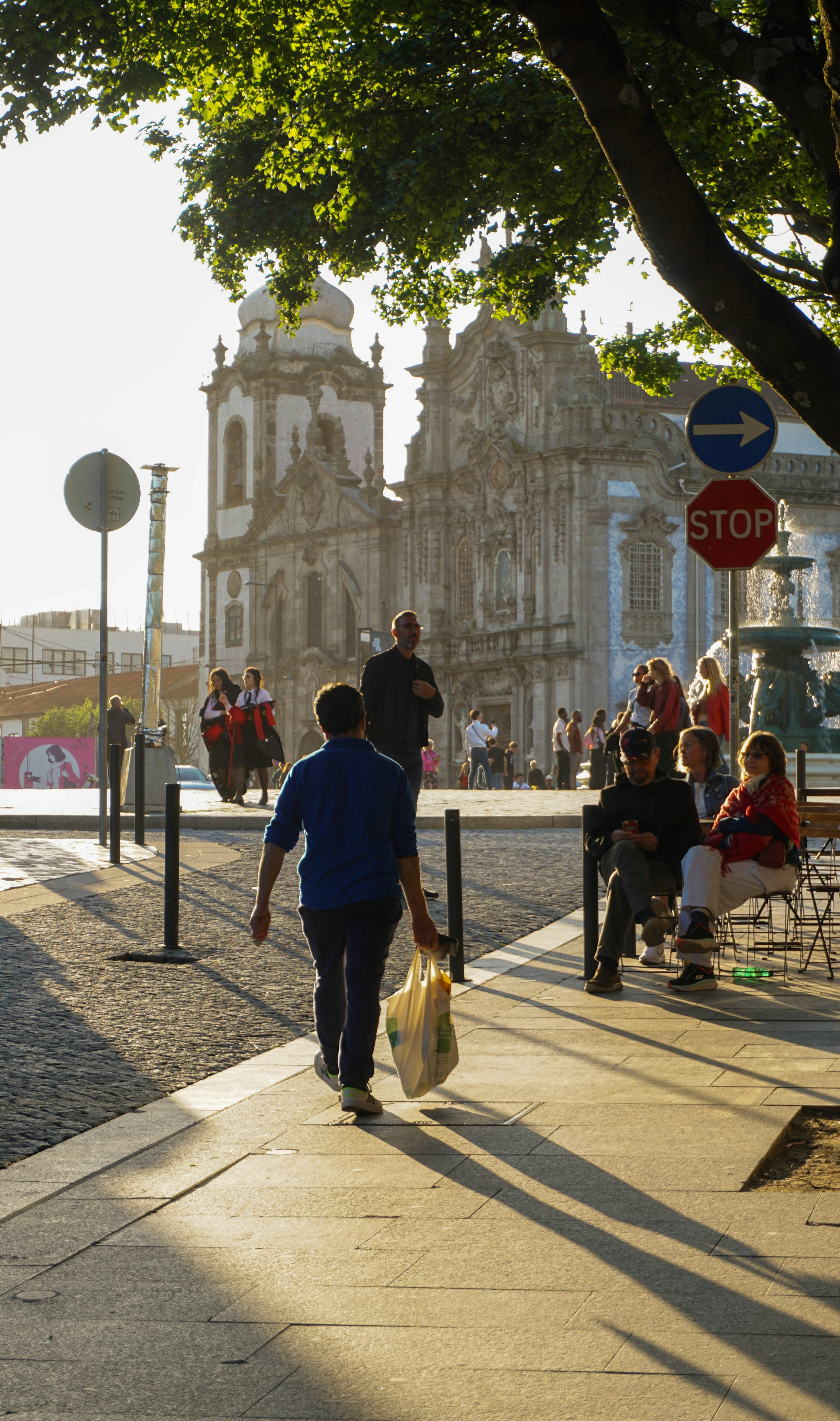 Man walks past a church in a sunny plaza.