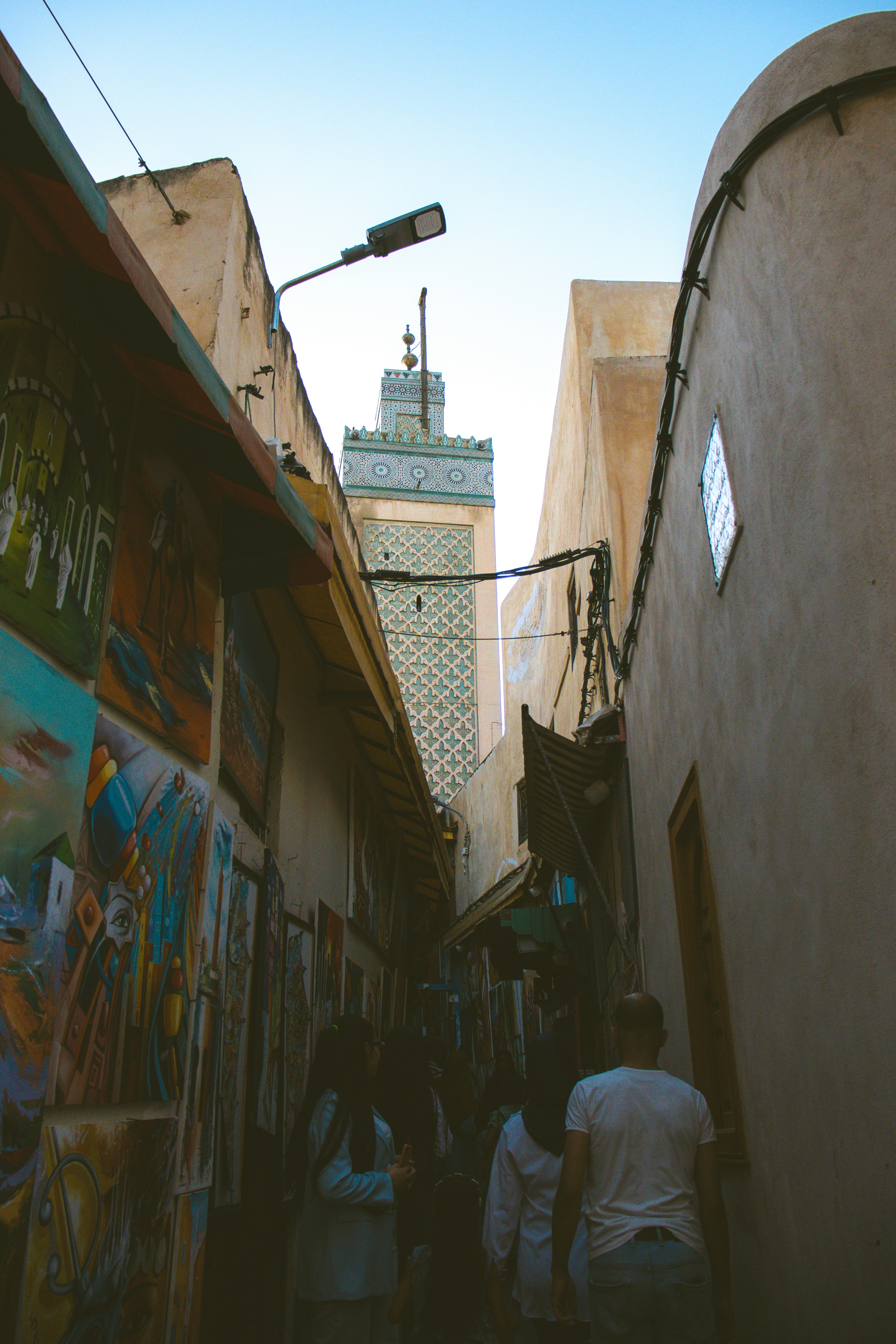 A narrow alley leads to a mosque's minaret.