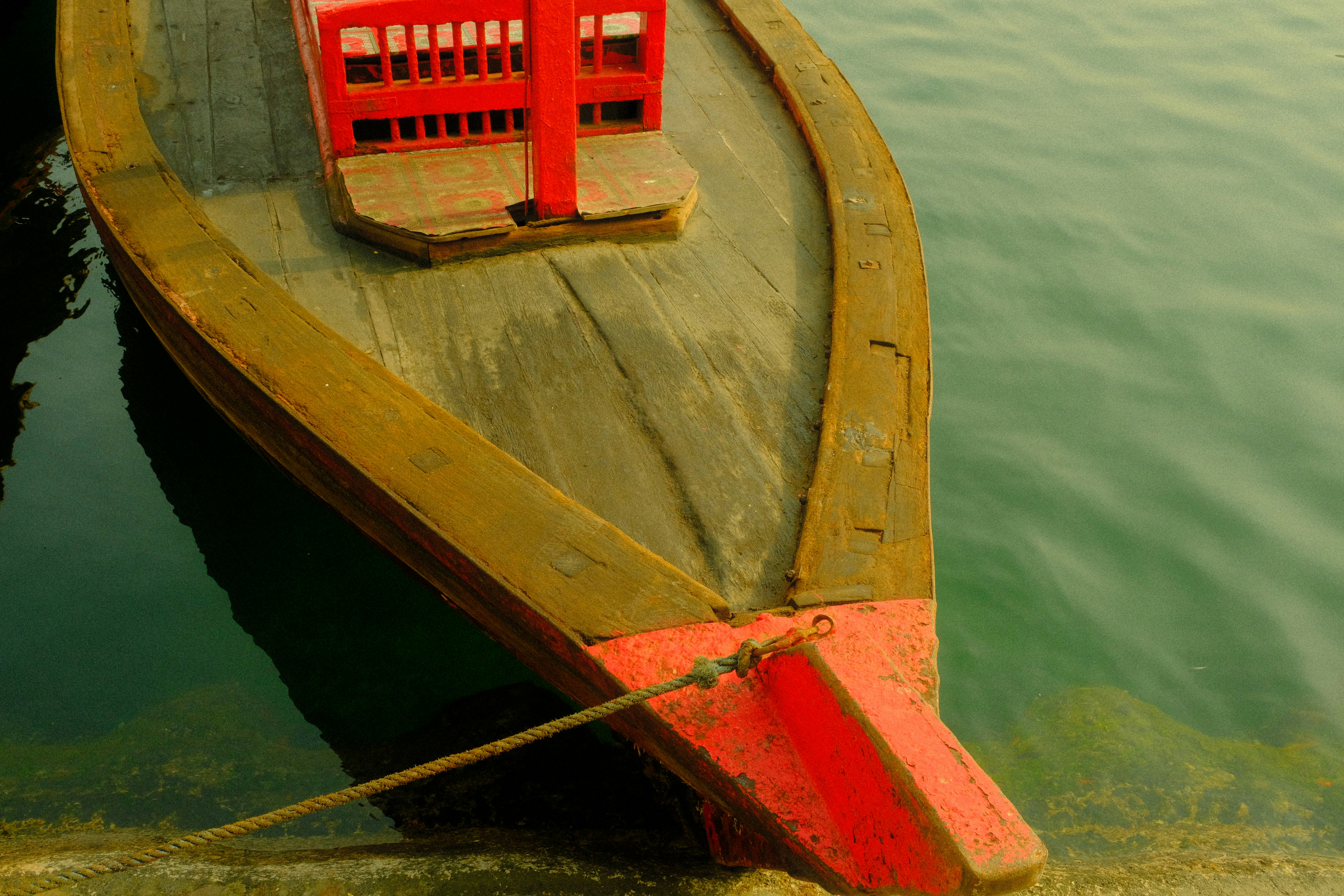 A wooden boat floats by the water's edge.