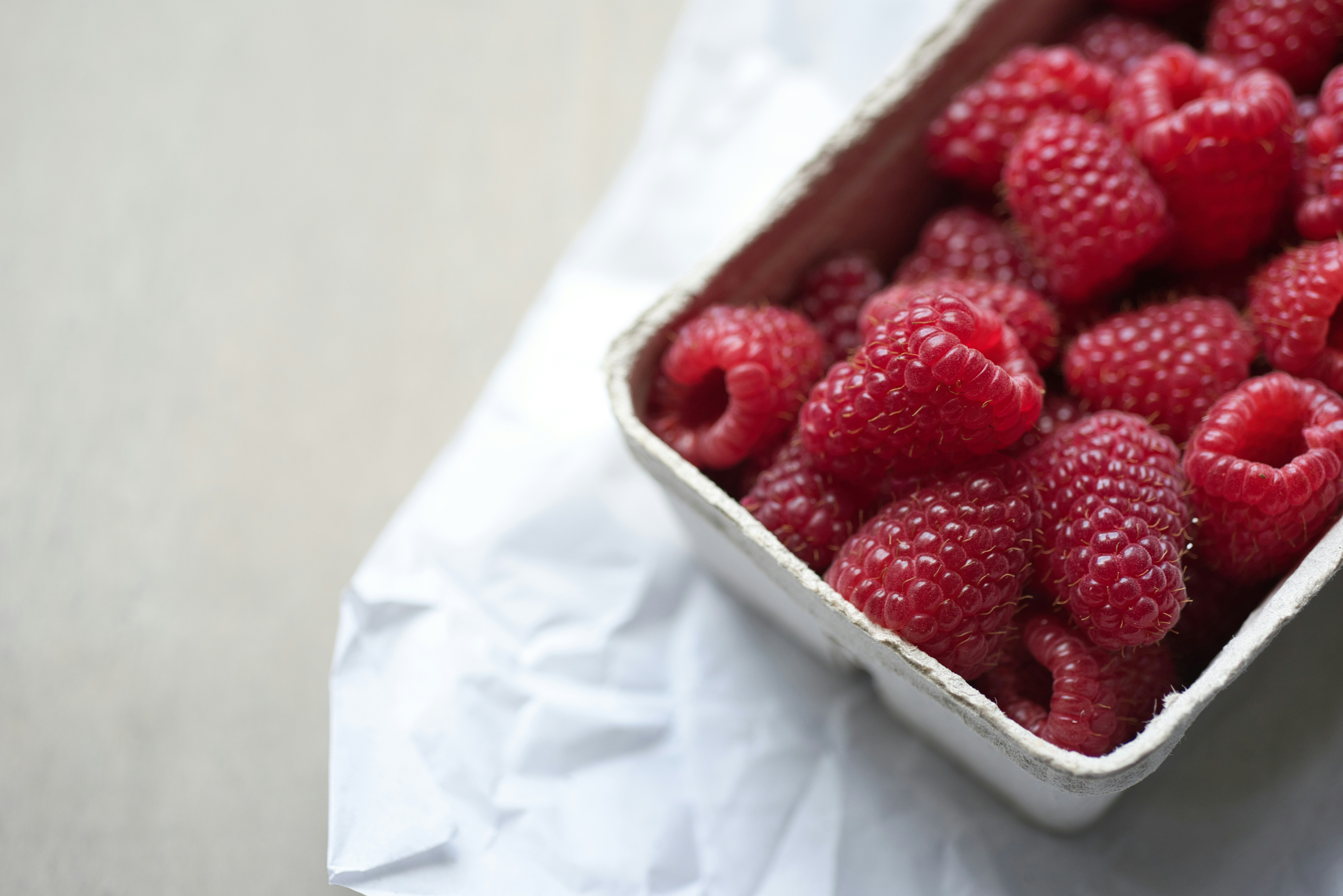 Sweet summer raspberries arranged in a rustic container. Healthy and colorful raspberries displayed in eco-friendly packaging.