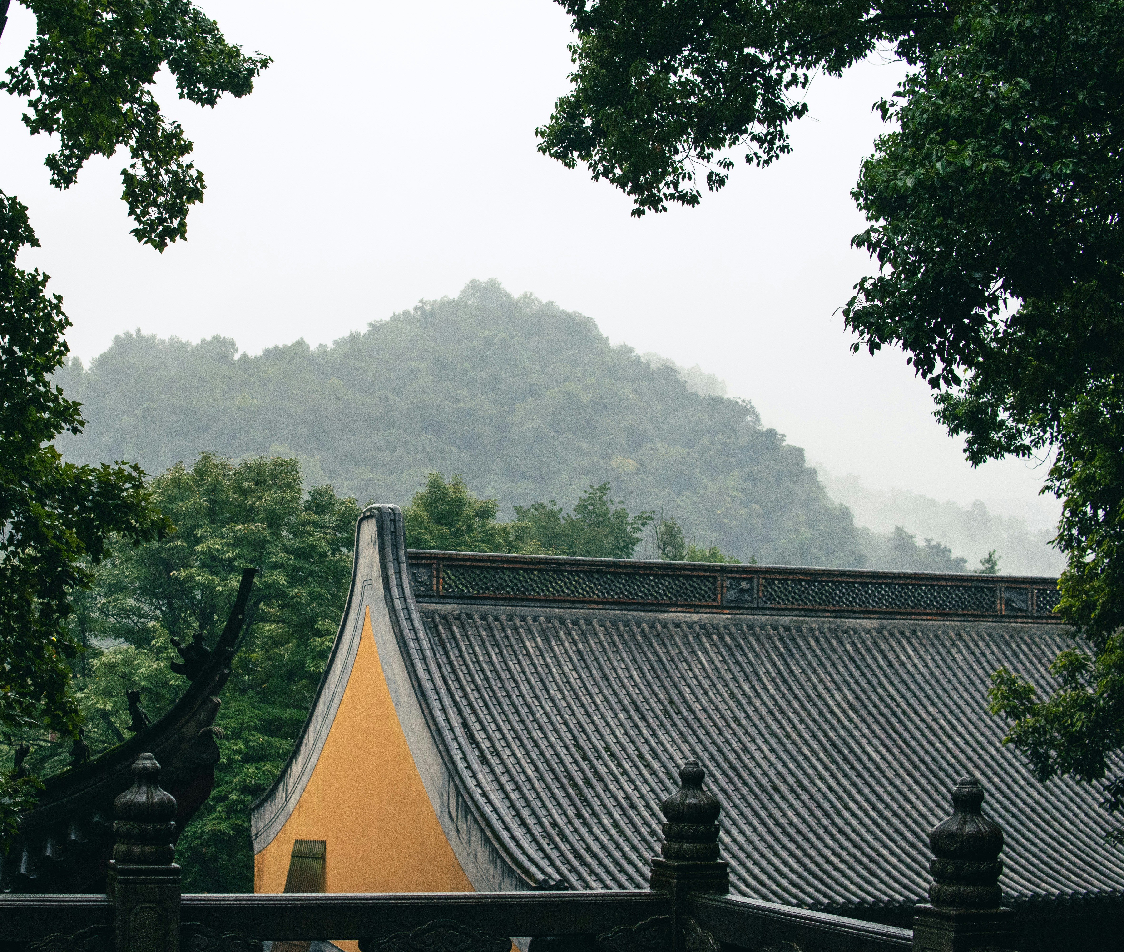 A temple roof faces a misty mountain.