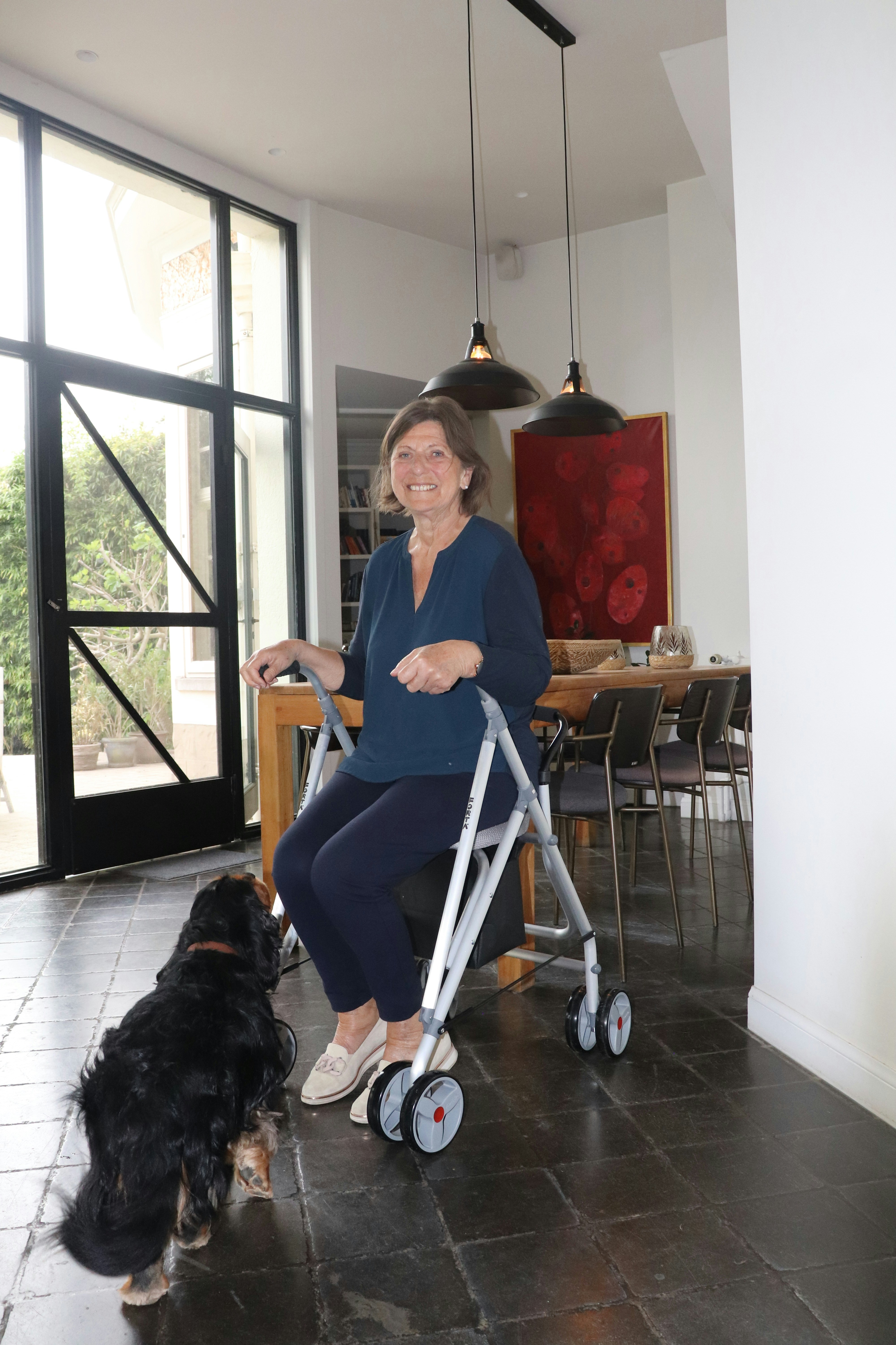 Warm Indoor Moment: A Woman on a Rollator Shares a Quiet Pause with a Dog