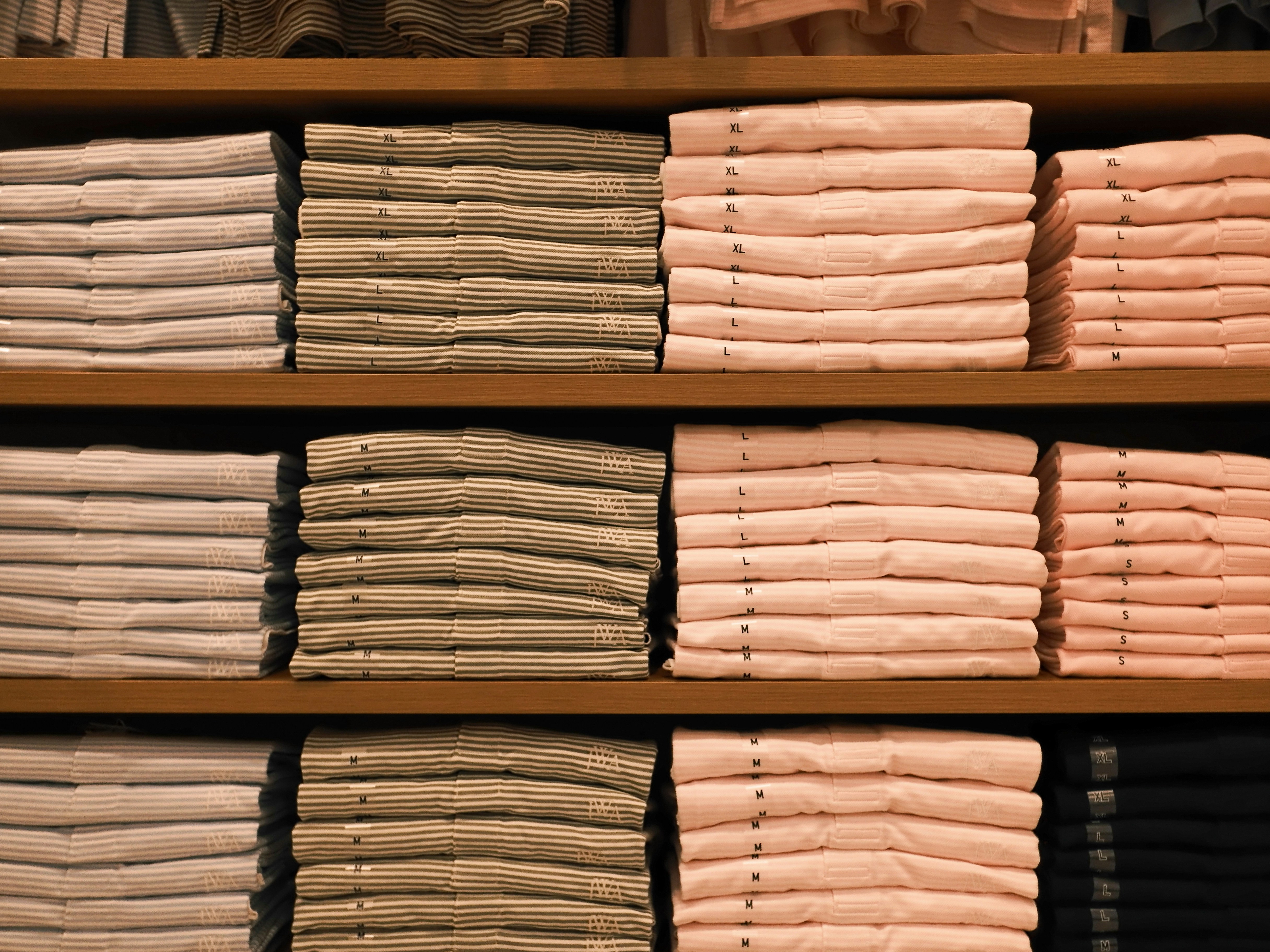 Neatly folded shirts stacked on wooden shelves.
