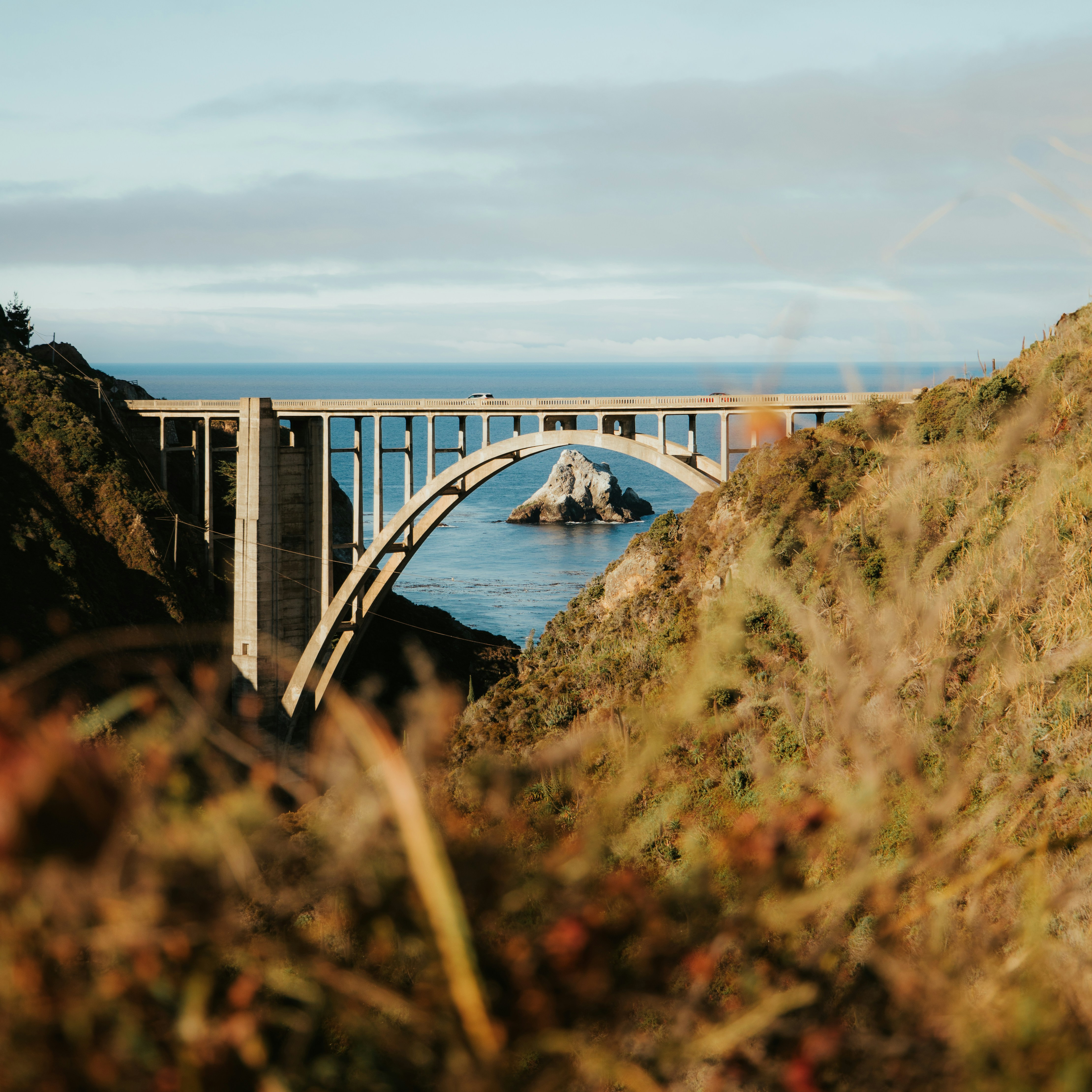 A bridge arches over the ocean.
