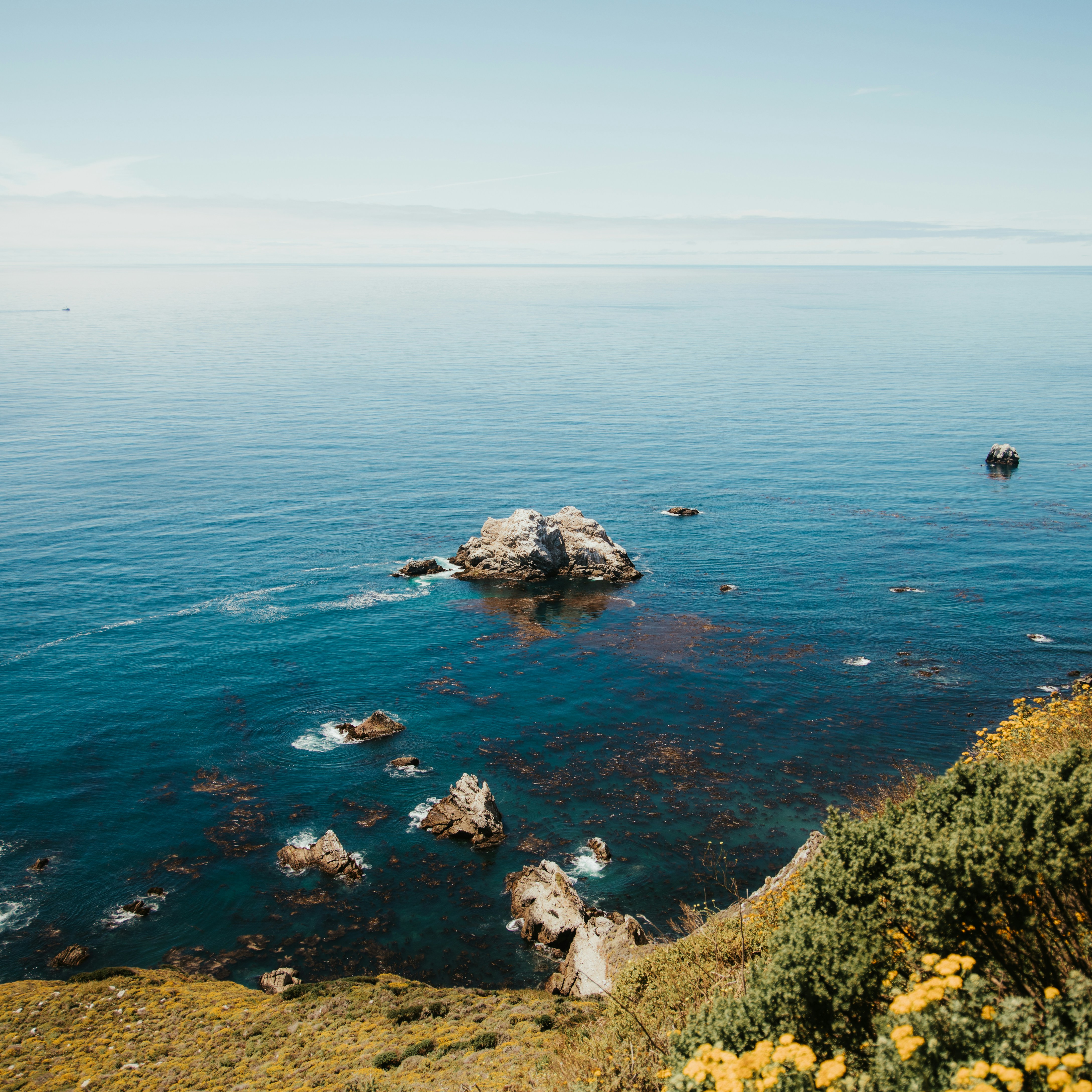 Ocean view with rocks and a blue sky.