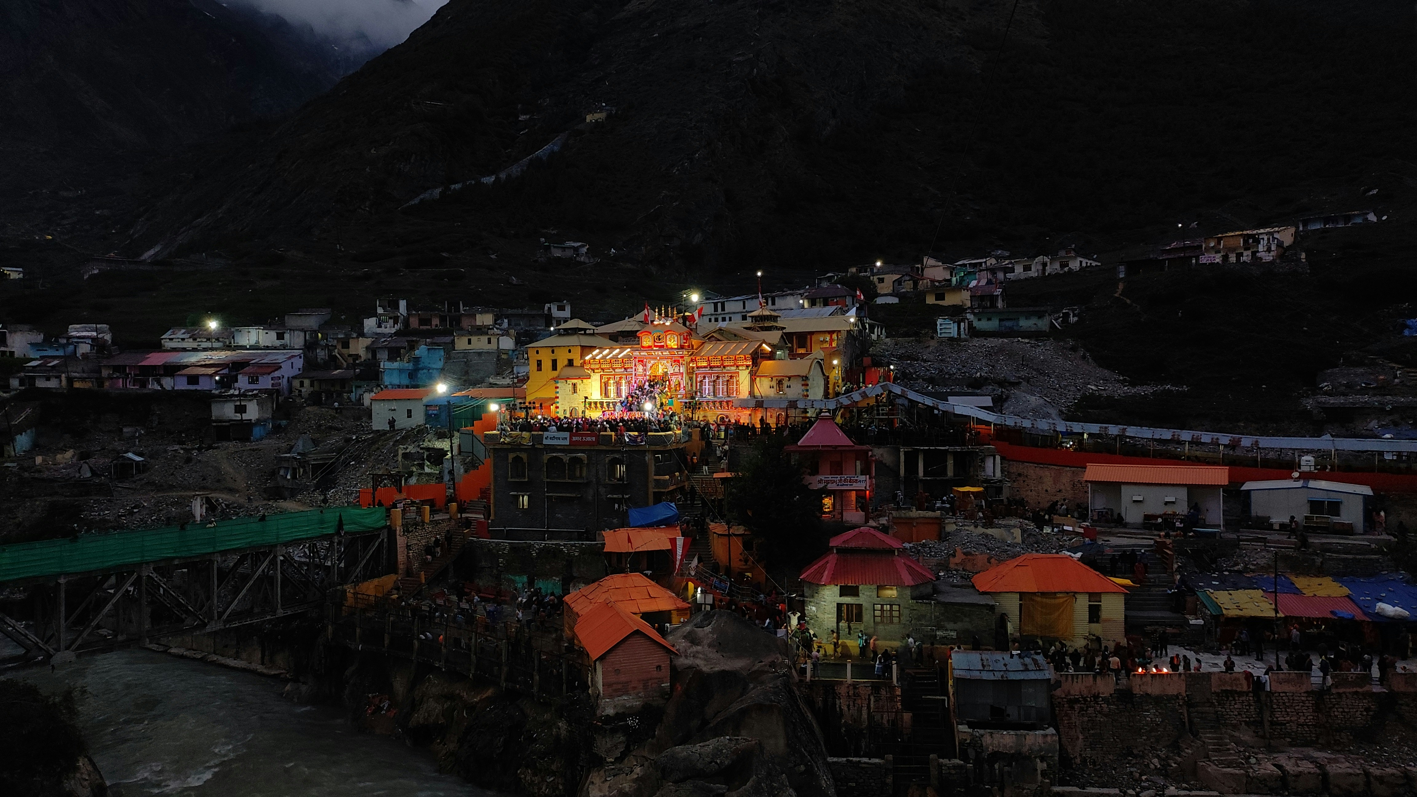A lit-up temple nestled in a mountainous area.