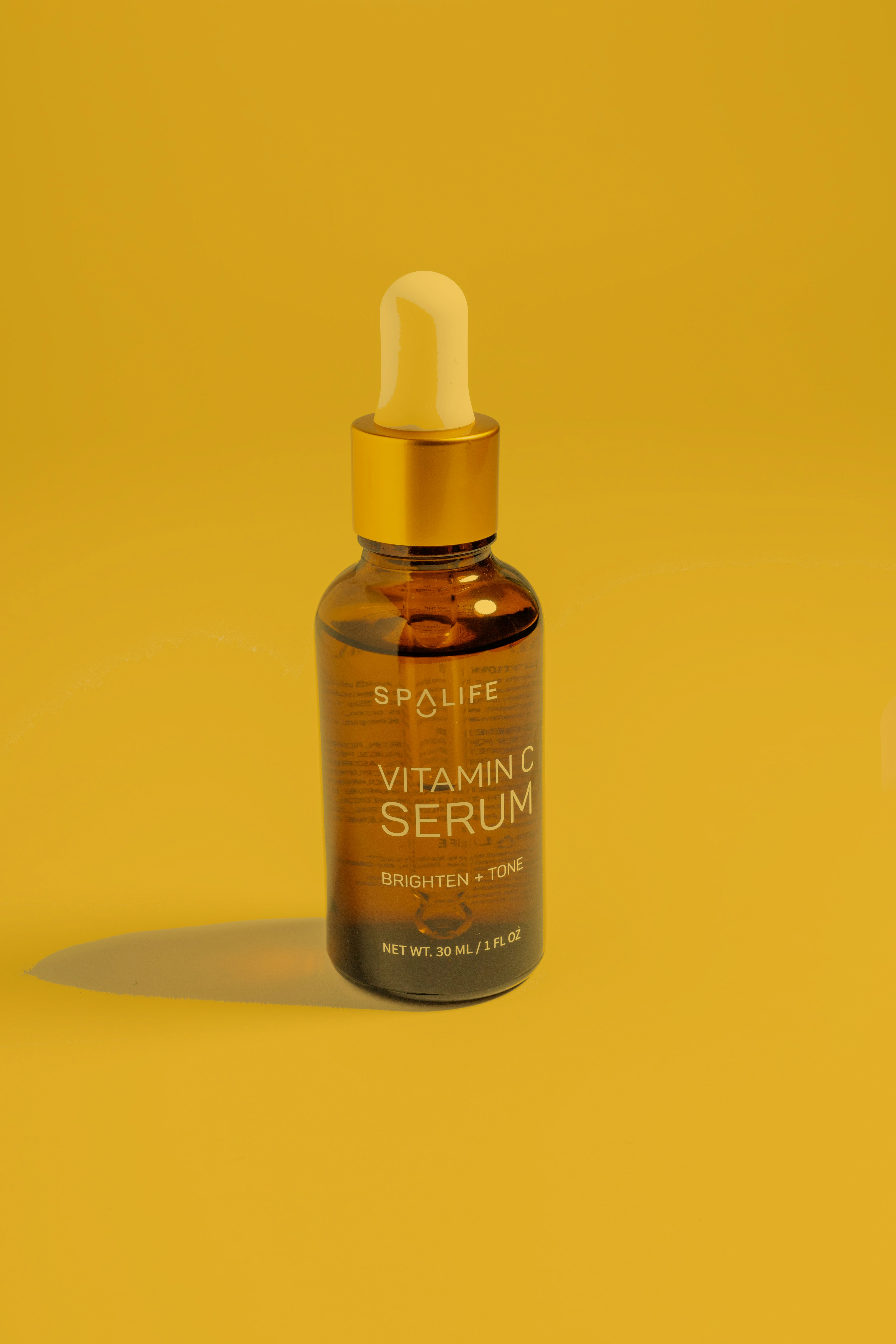Here's a caption for the image: vitamin c serum bottle against a yellow ...