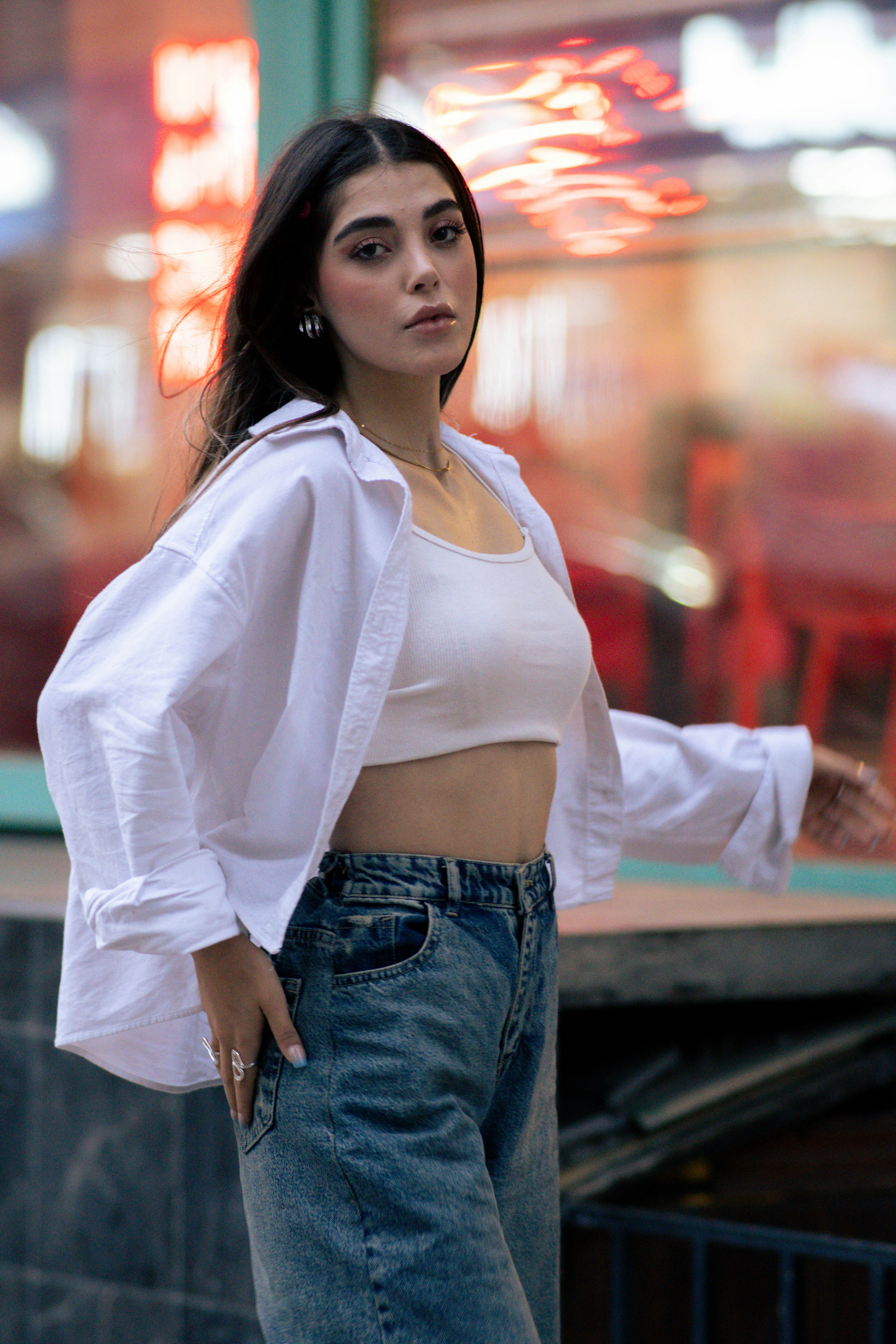 Photograph by Amin Naderloei | Stylish woman poses outdoors, illuminated by neon lights.