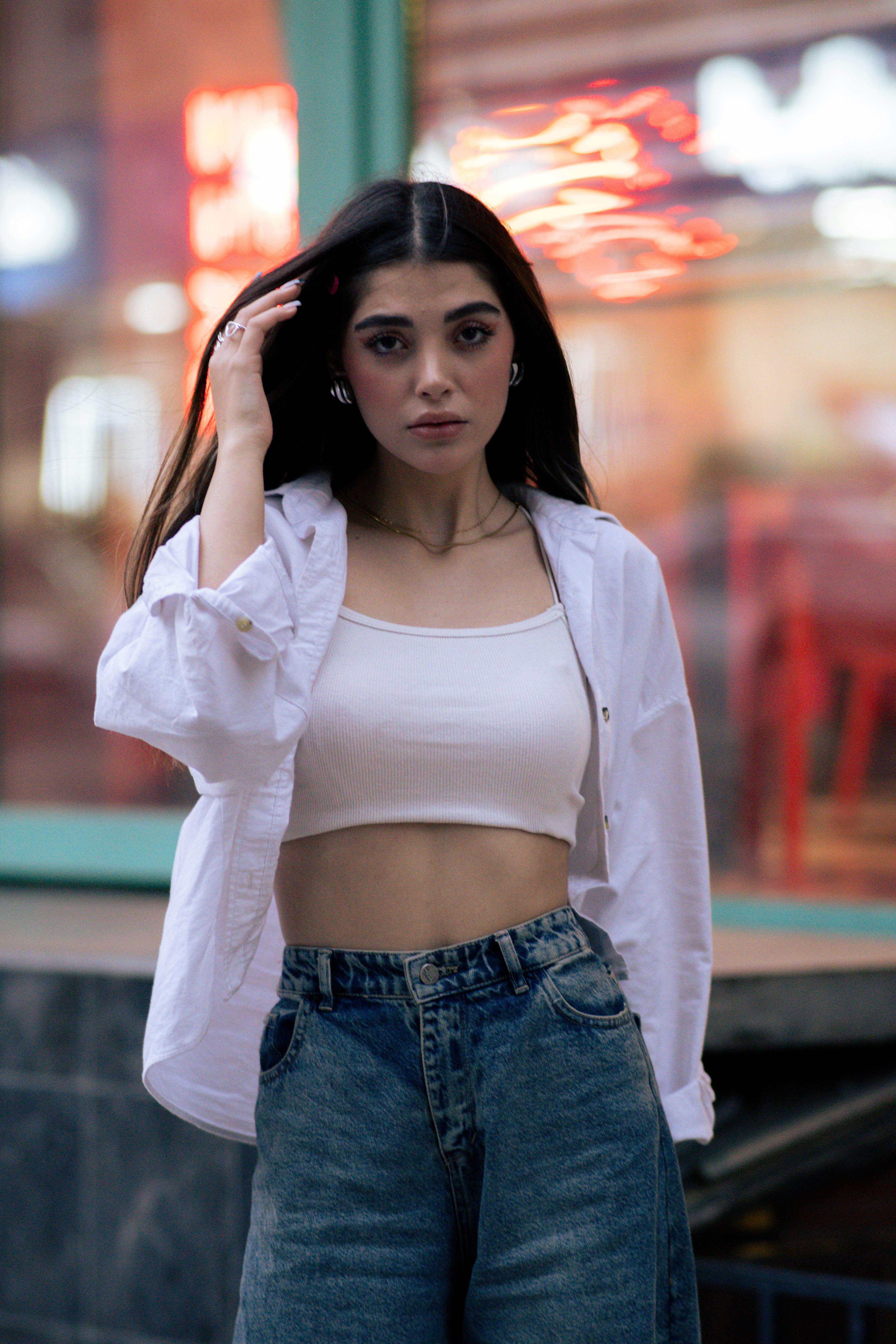 Photograph by Amin Naderloei | Woman poses in an urban setting, hands in hair.