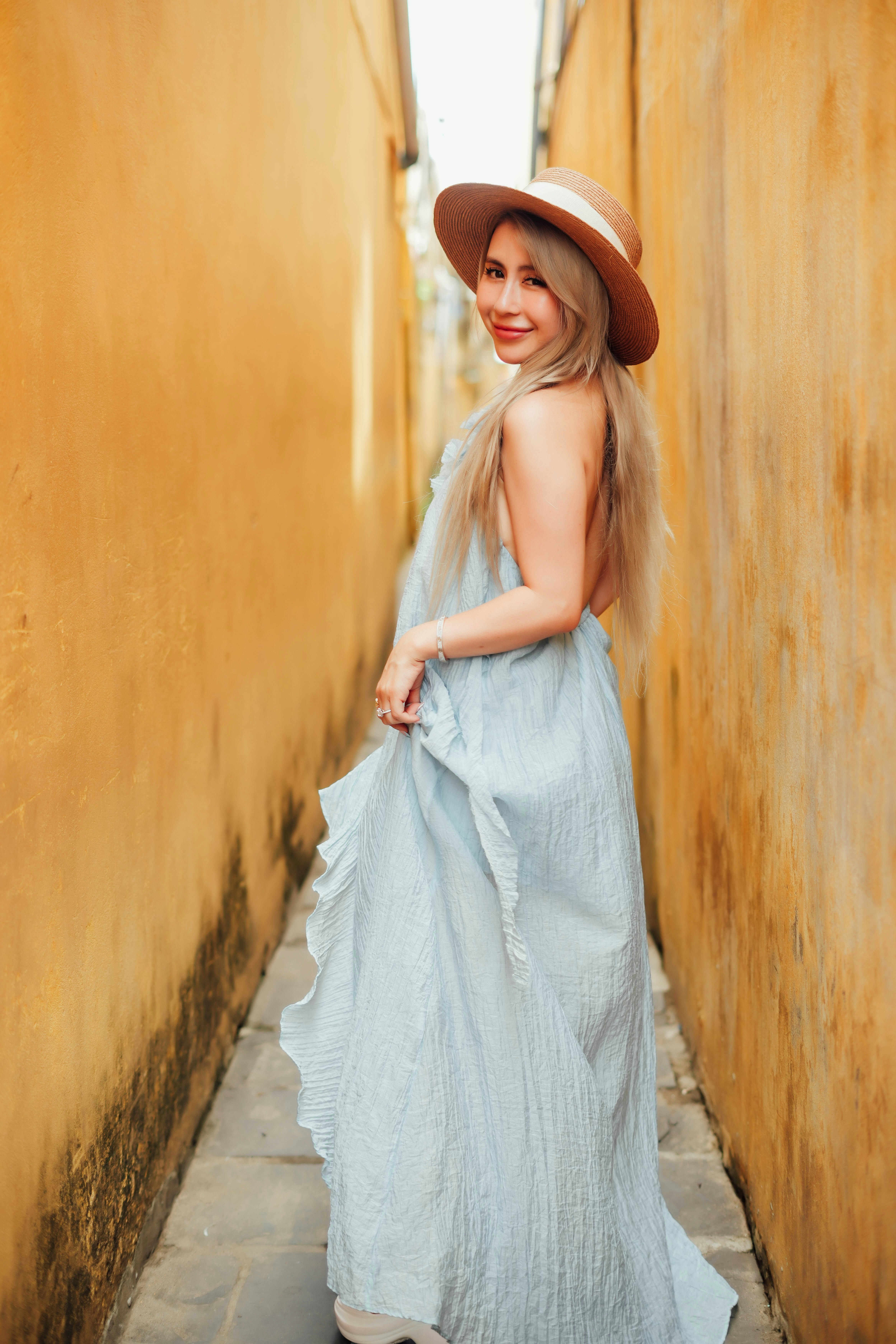 Woman in blue dress poses in a yellow alley.