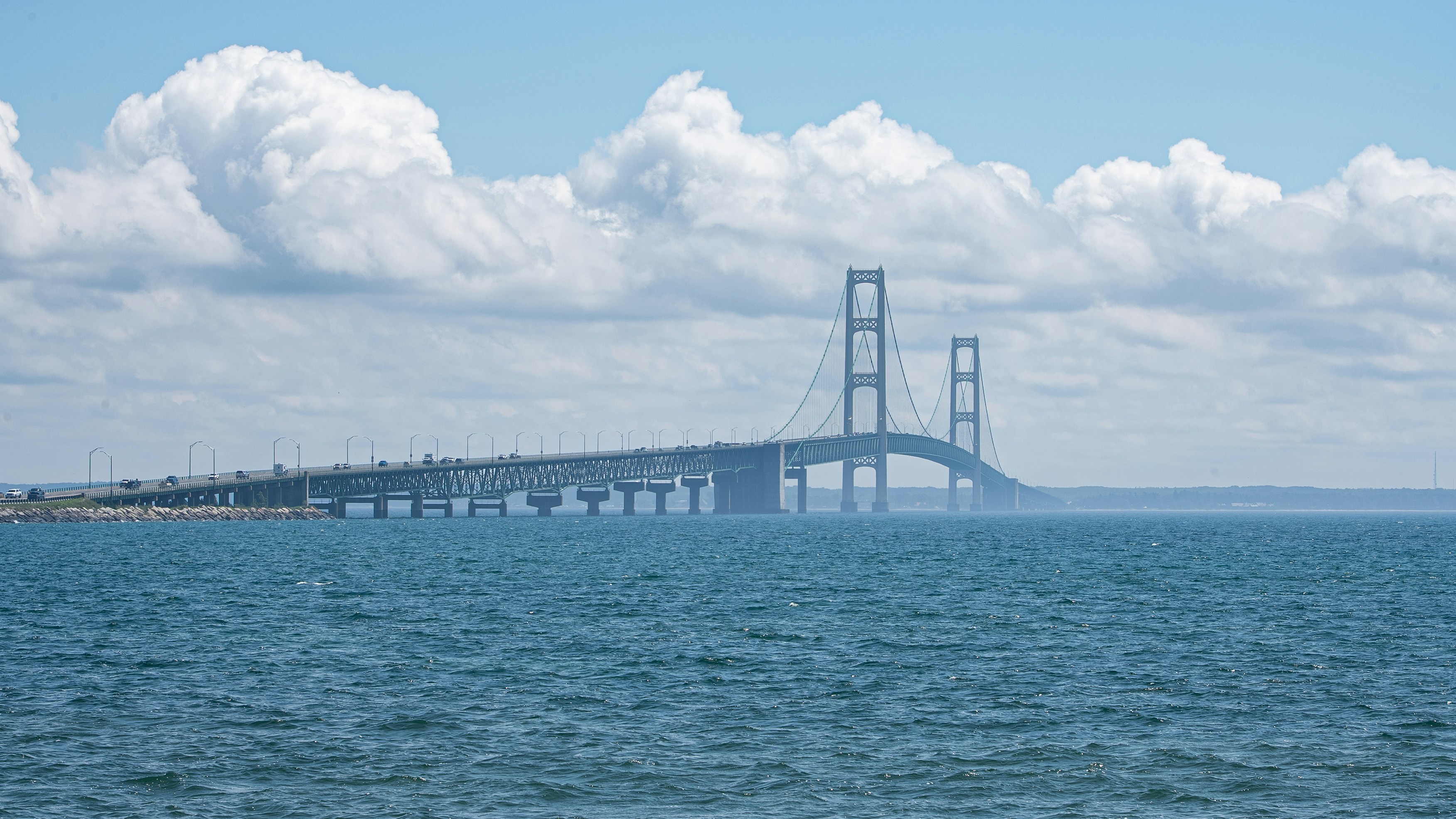 The mackinac bridge spans across a blue lake.