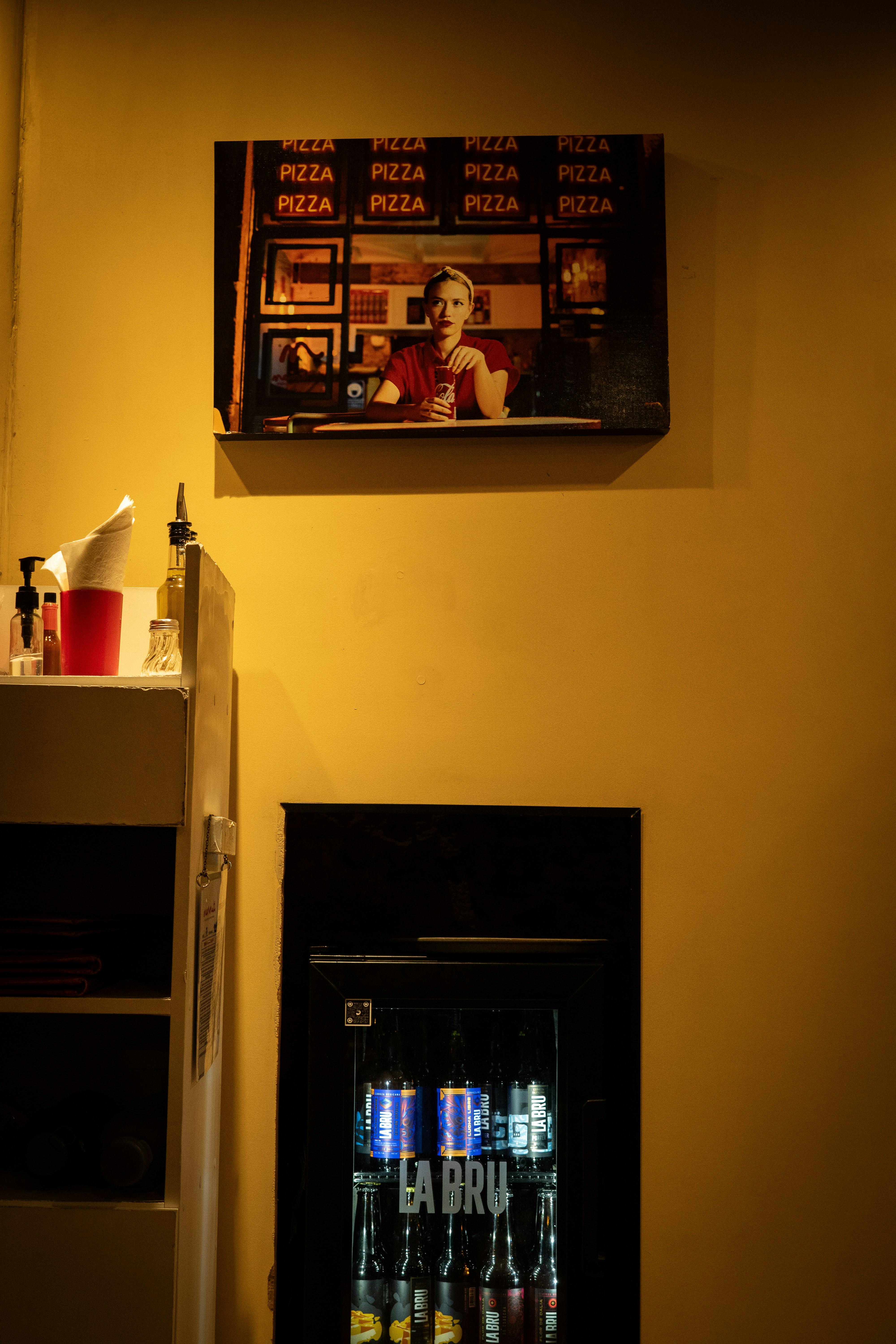 Restaurante Mamut | A pizza picture is hanging on a yellow wall.