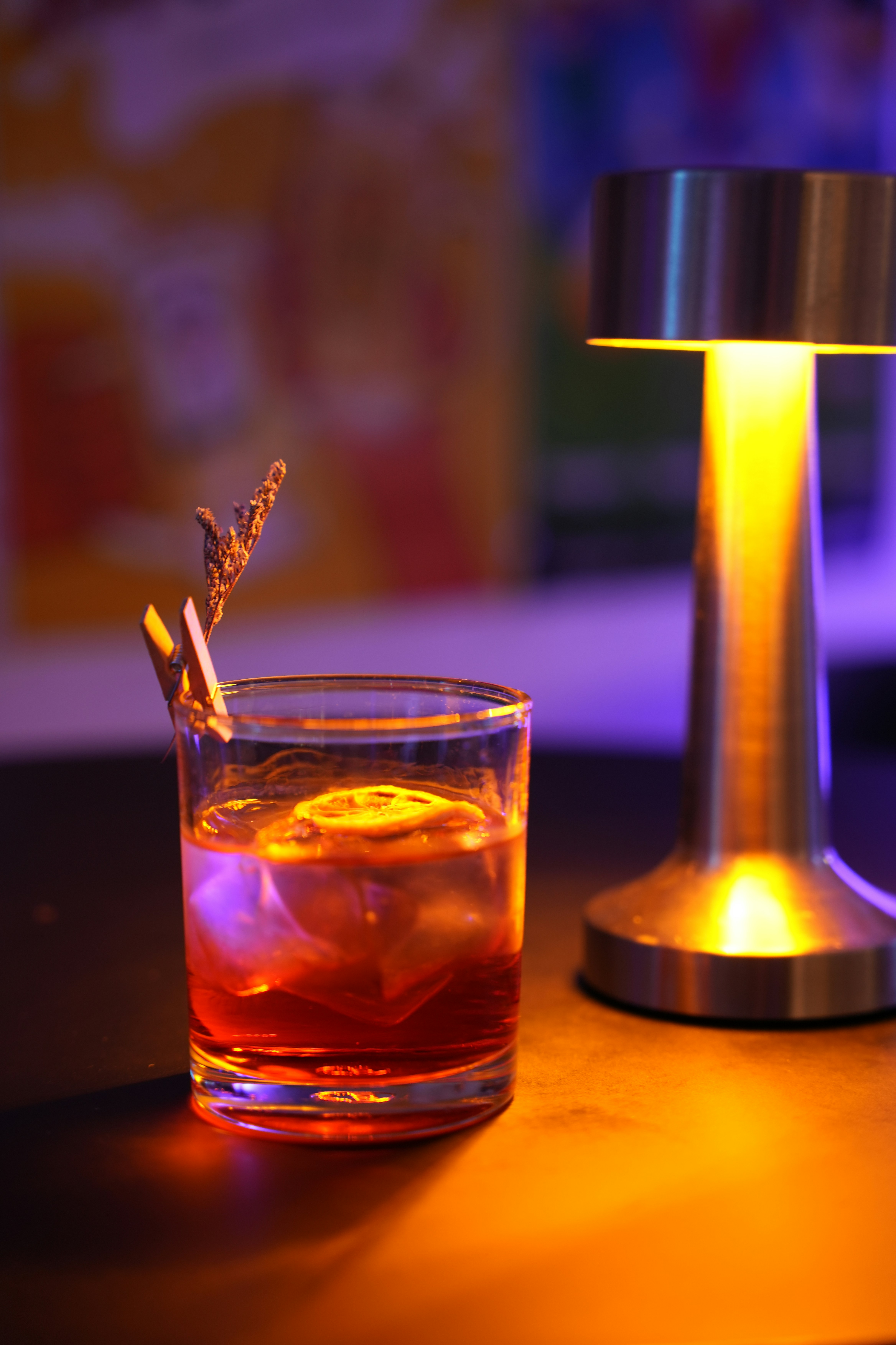 A fancy cocktail sits near a glowing lamp